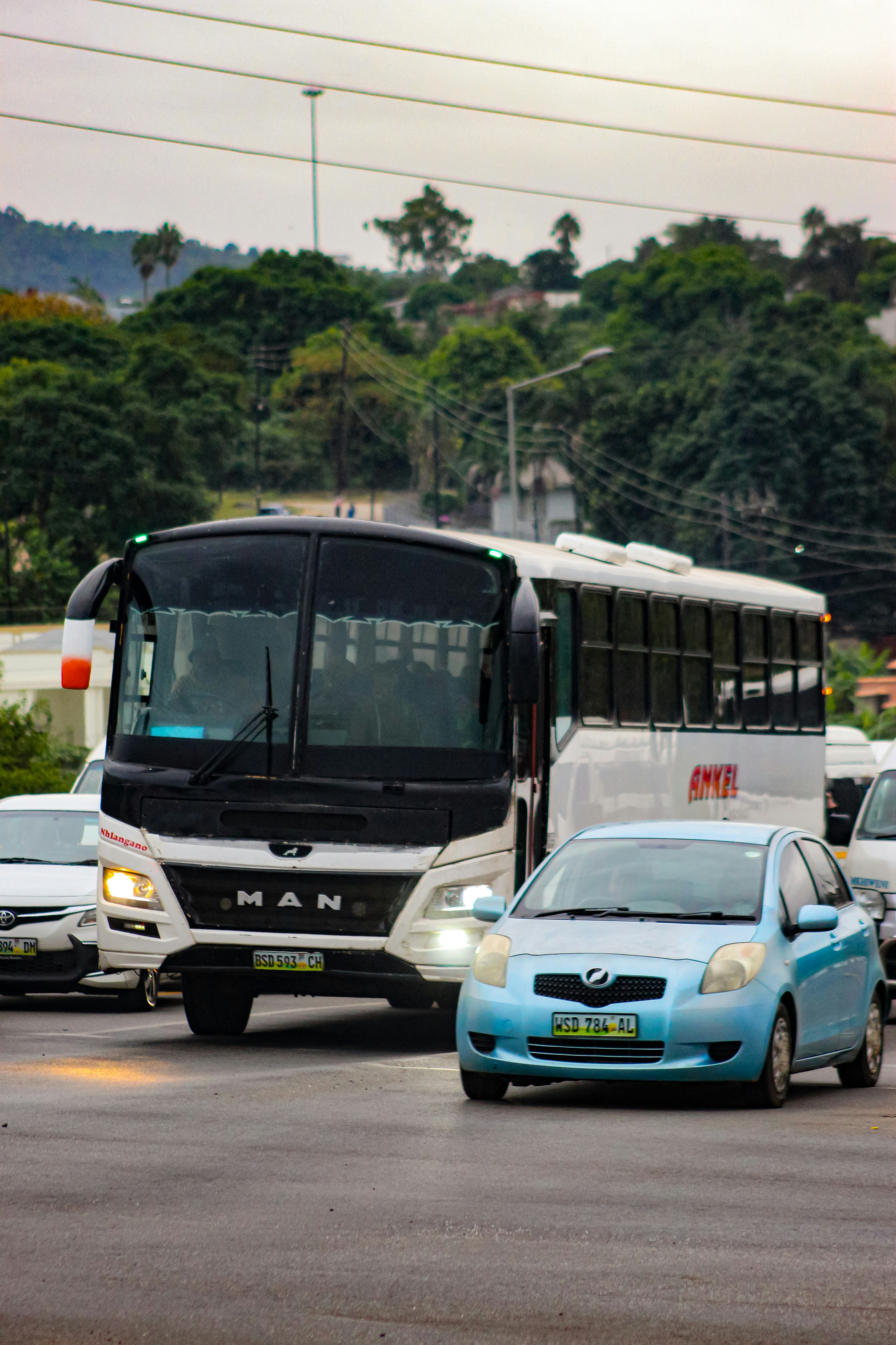 Street Bus Confronts a Blue Hatchback in a Busy Urban Mix