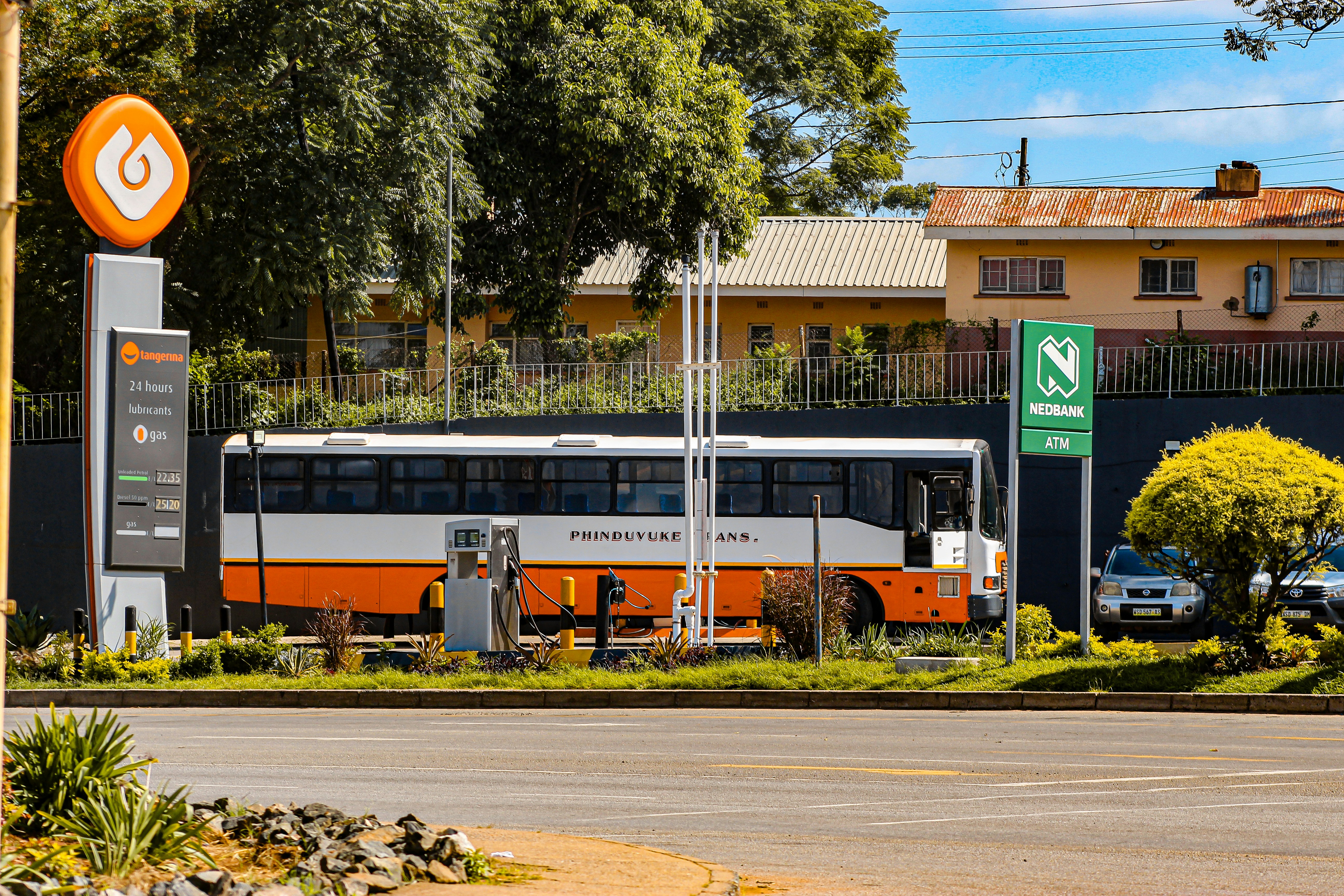Bright Orange-Striped Bus at a Modern Service Station