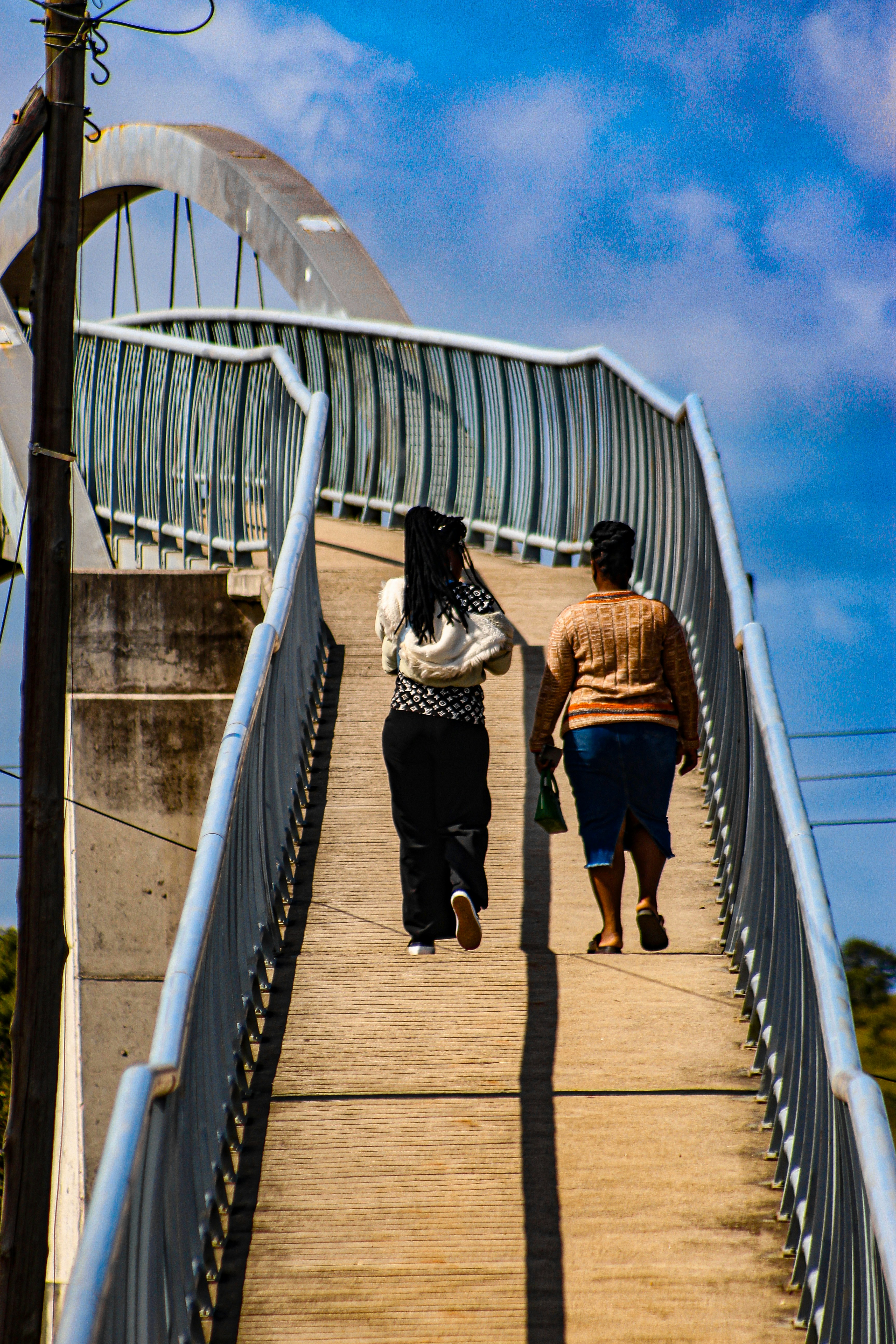 Bridge Walk: Two Travelers Treading Toward the Sky
