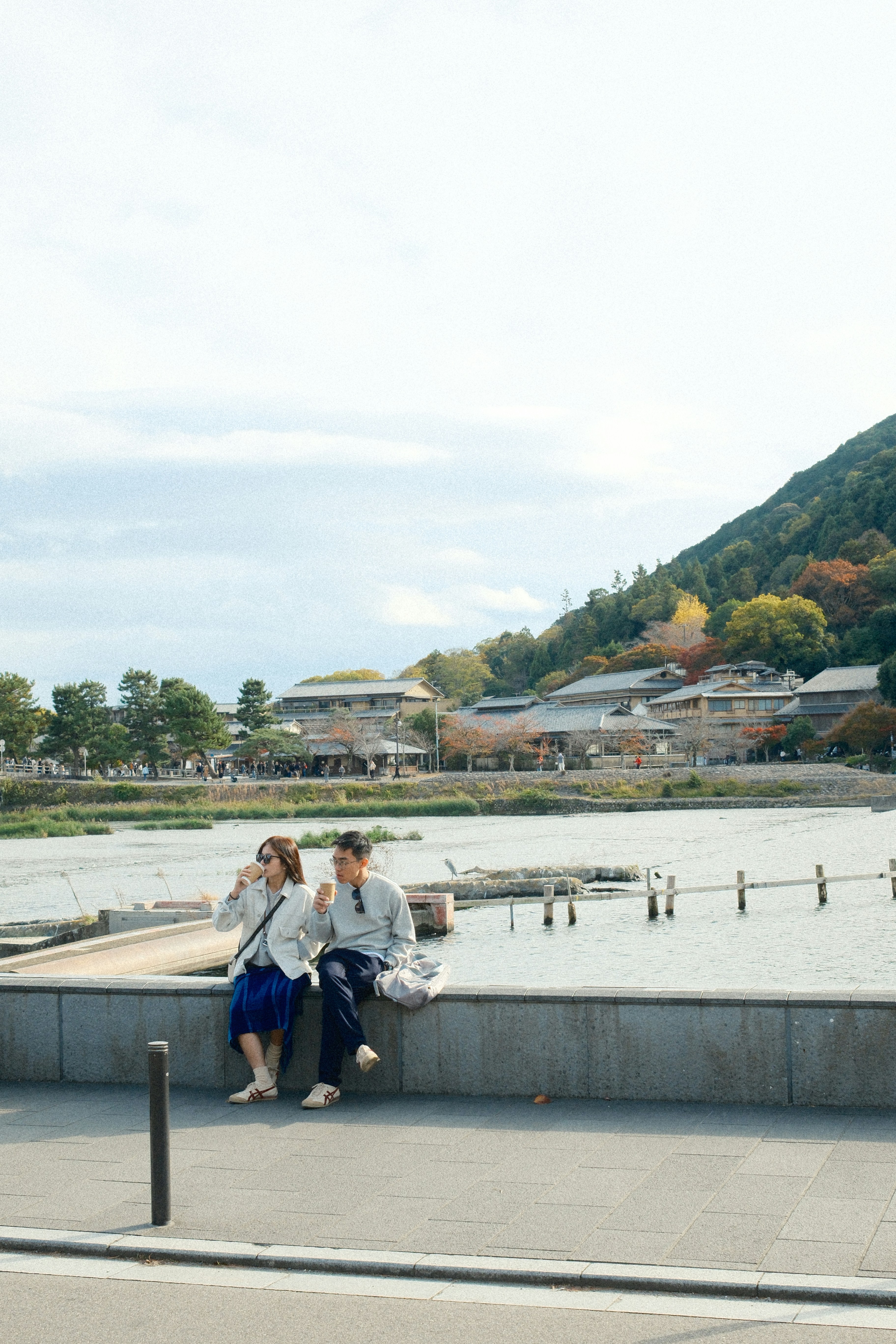 Couple by the riverside promenade under autumn light