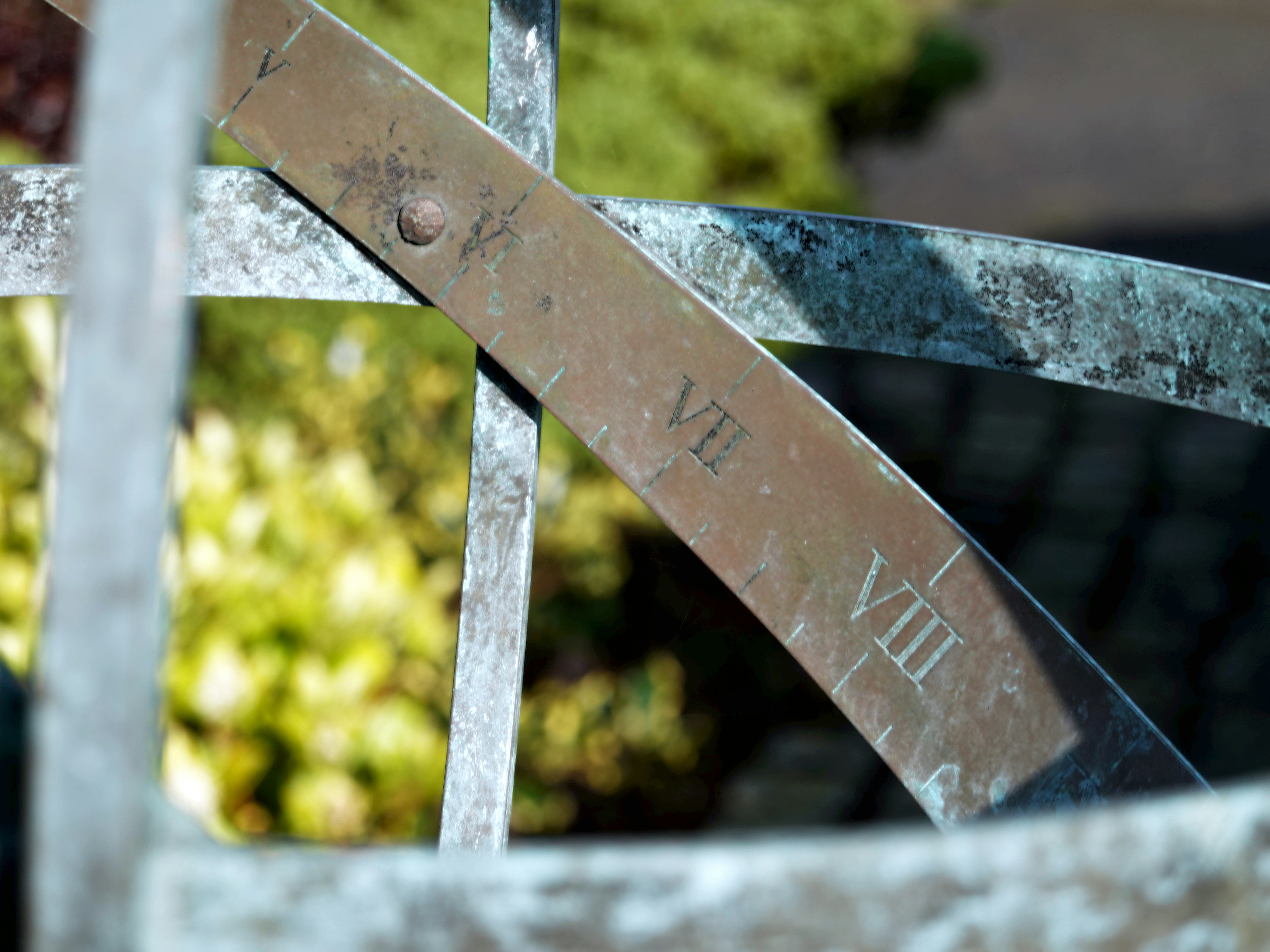 A Weathered Arc: Rusted Struts Framing a Quiet Garden
