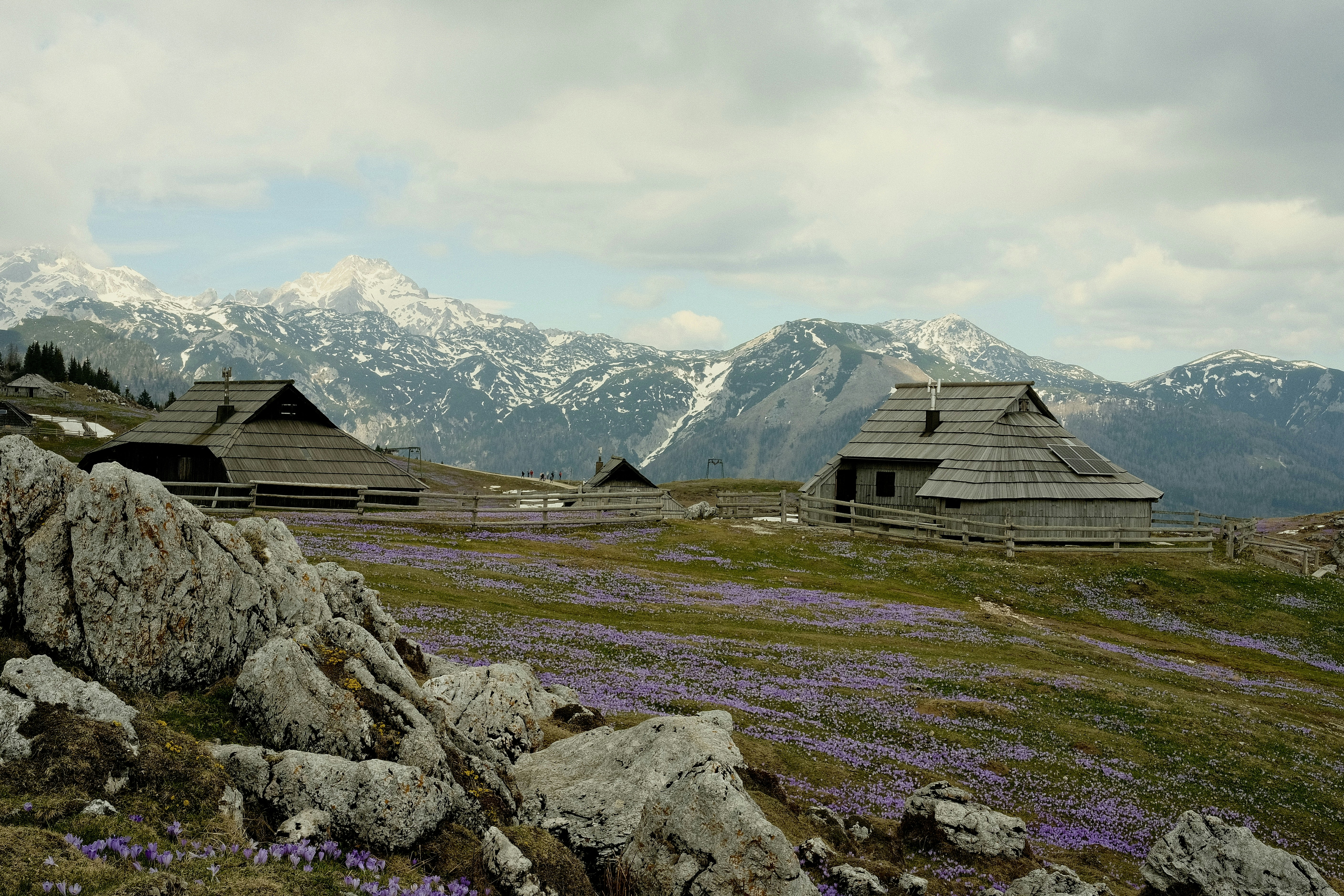 Stone cabins beneath snow-kissed peaks on a sprawling alpine meadow