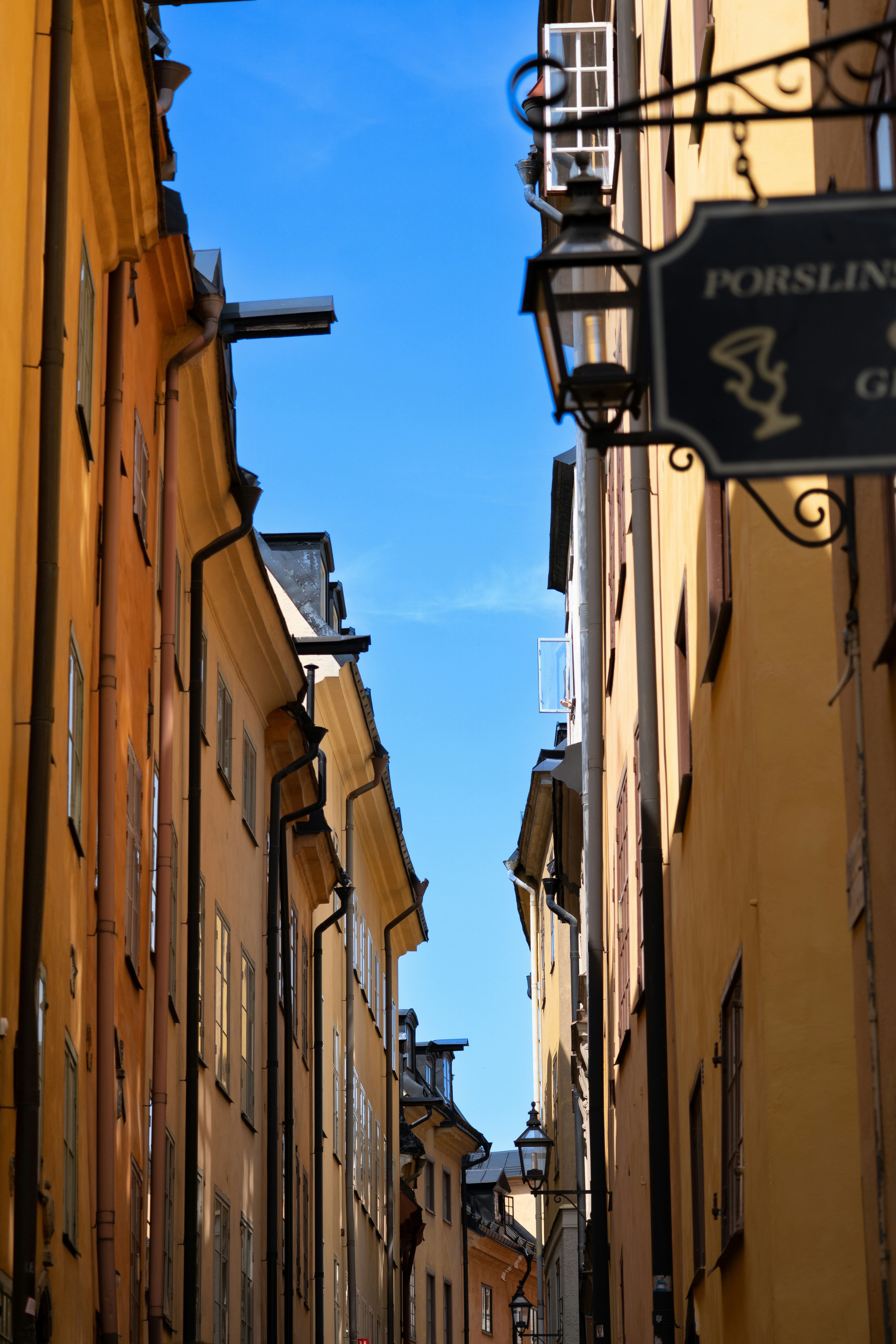 Narrow Street Horizon: Sunlit Facades and Blue Sky Between Historic Walls