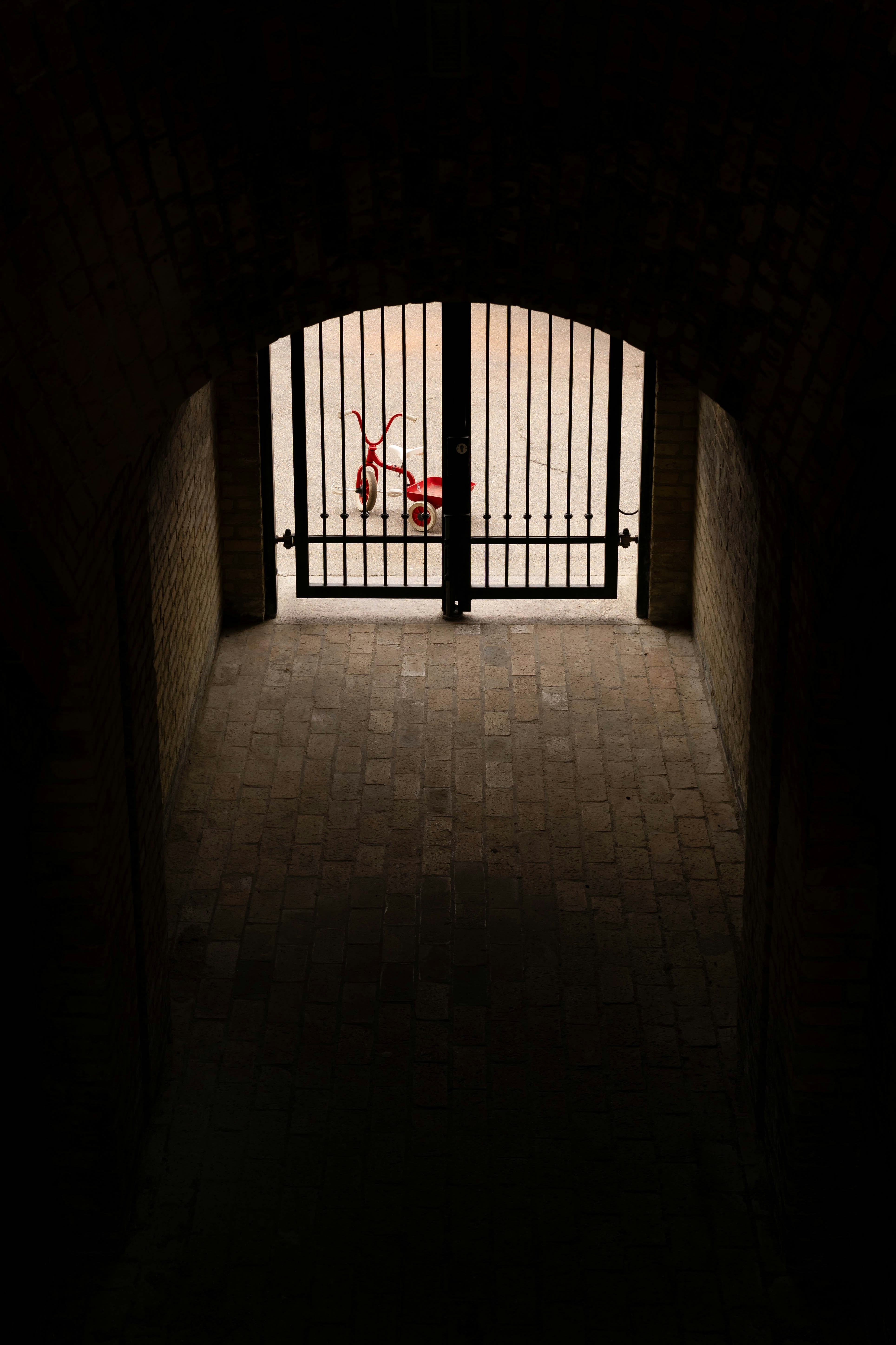 Red tricycle at the gate: light spilling from the tunnel
