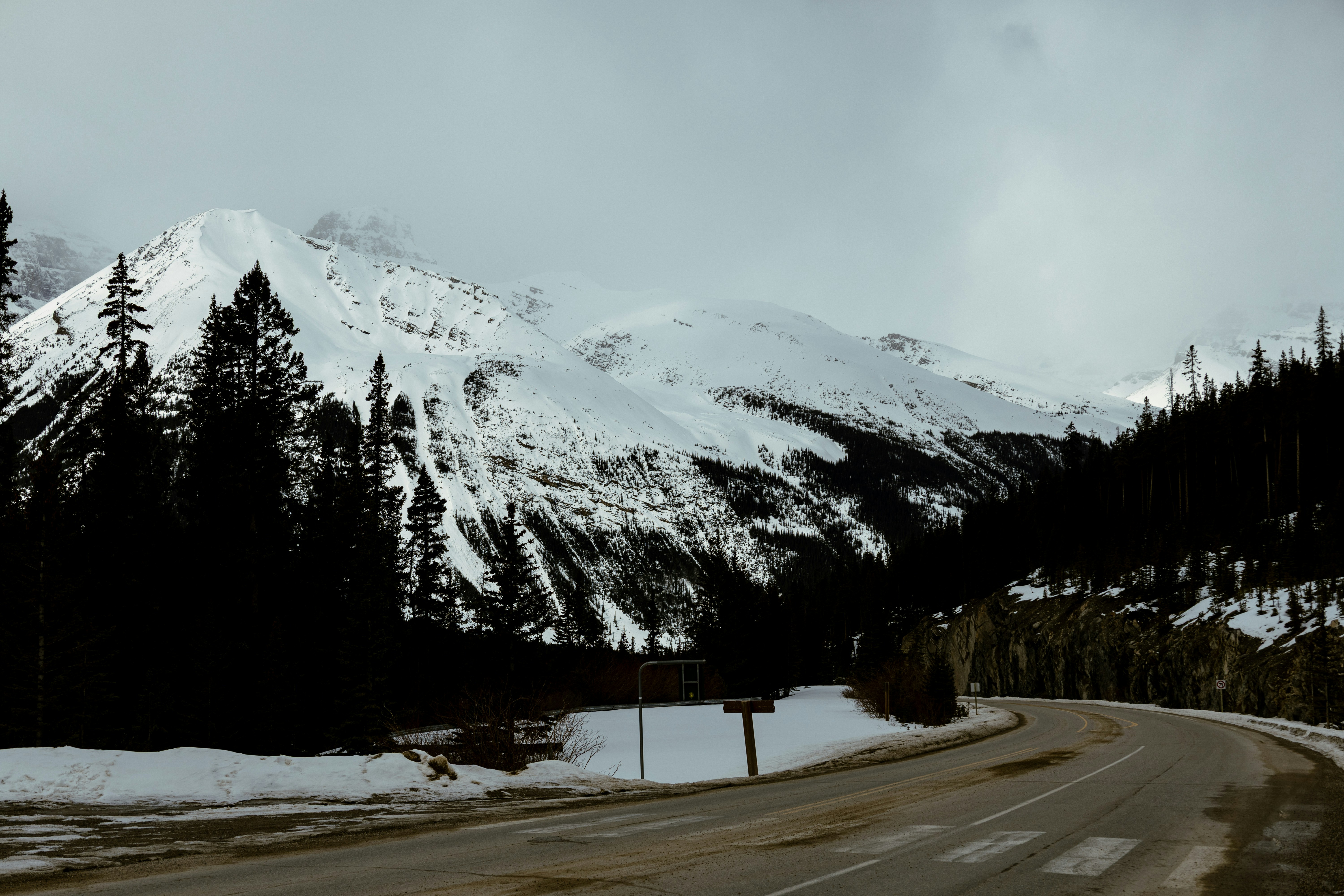 Snowbound Highway Curves Under a Looming Alpine Ridge