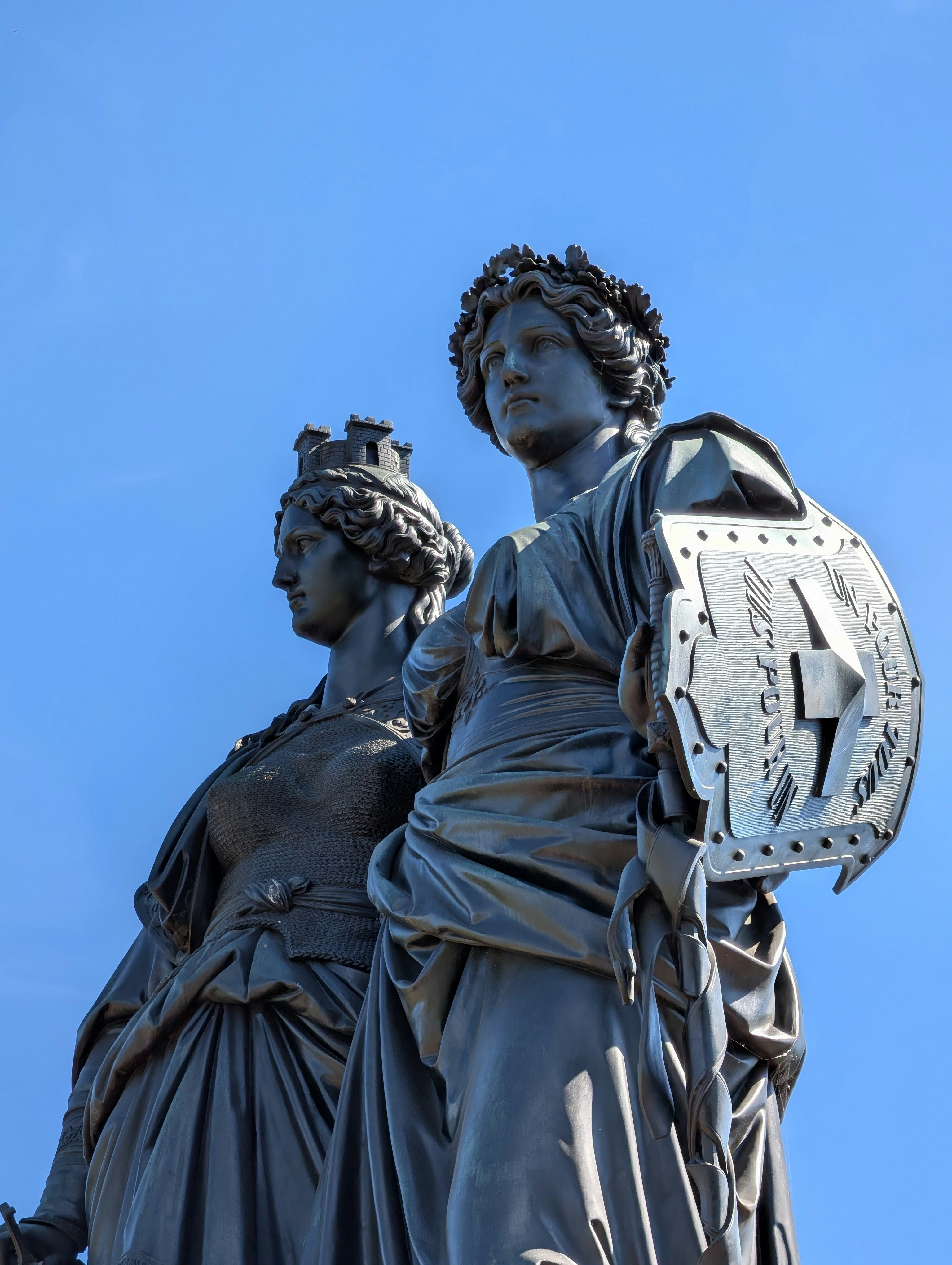Guardians of the Crest: Bronze Statues Against a Clear Blue Sky