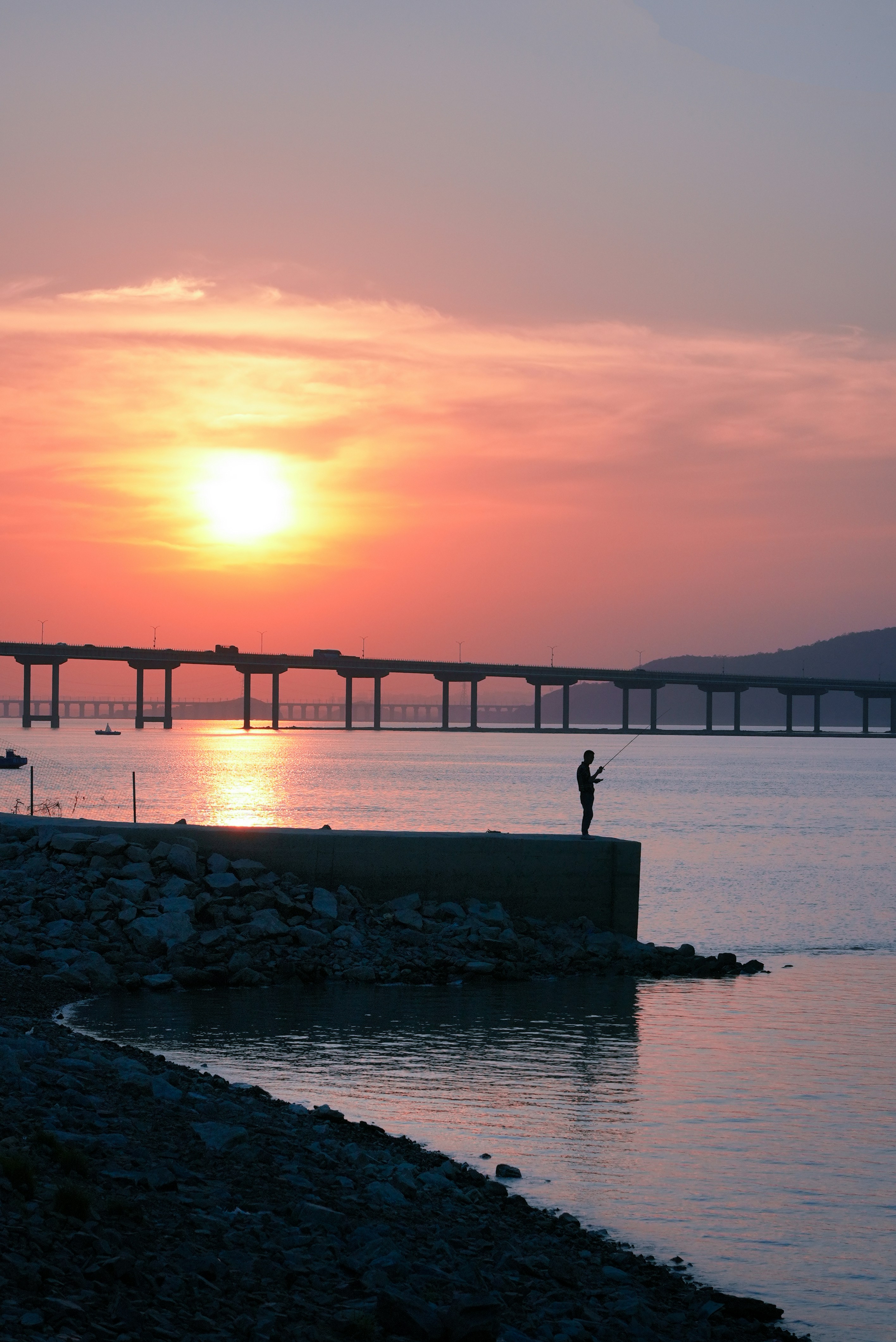 Sunset Pier: A Lone Fisherman at the Edge of Calm Waters