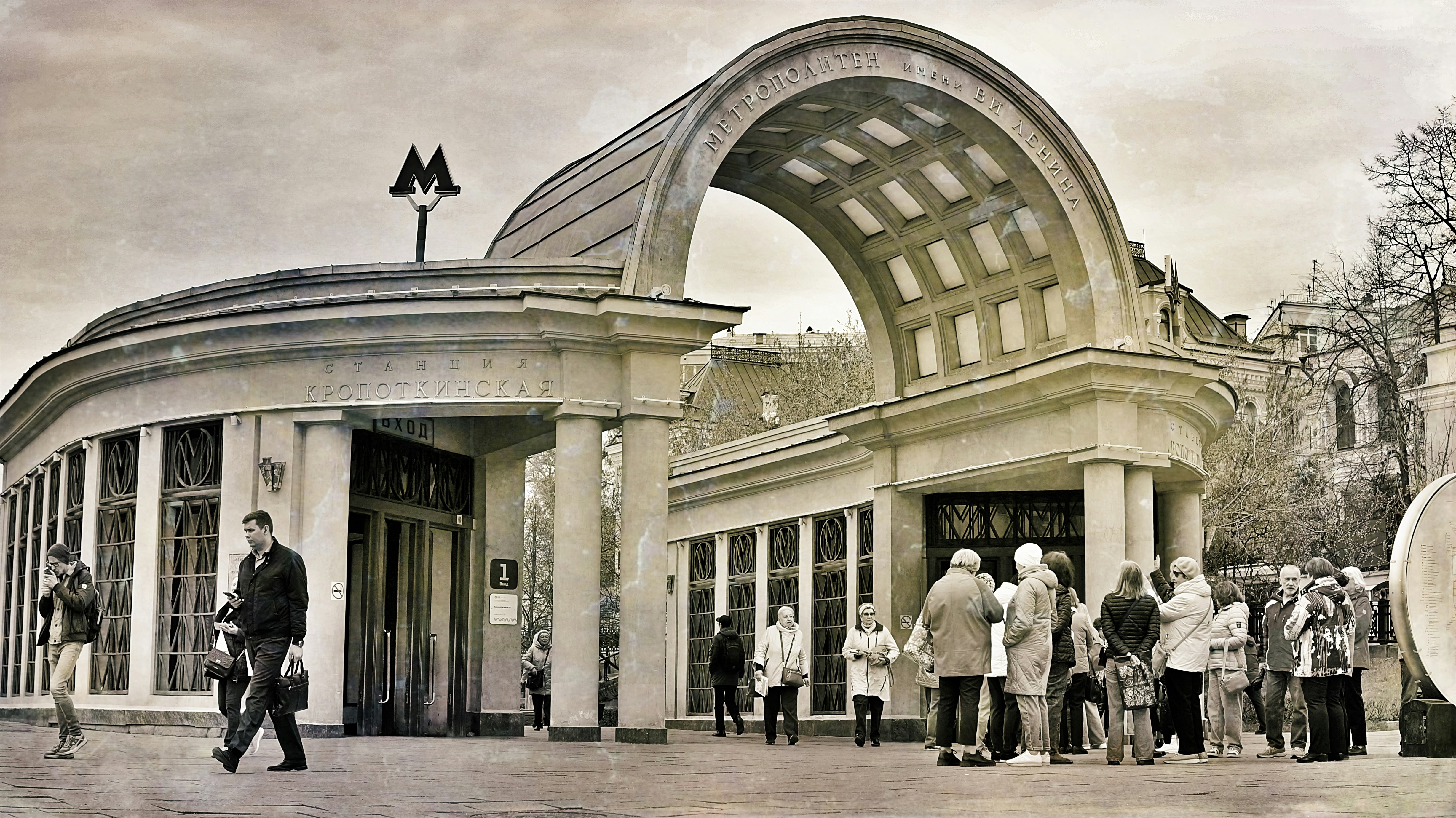 People gather at a vintage metro entrance under a curved arch