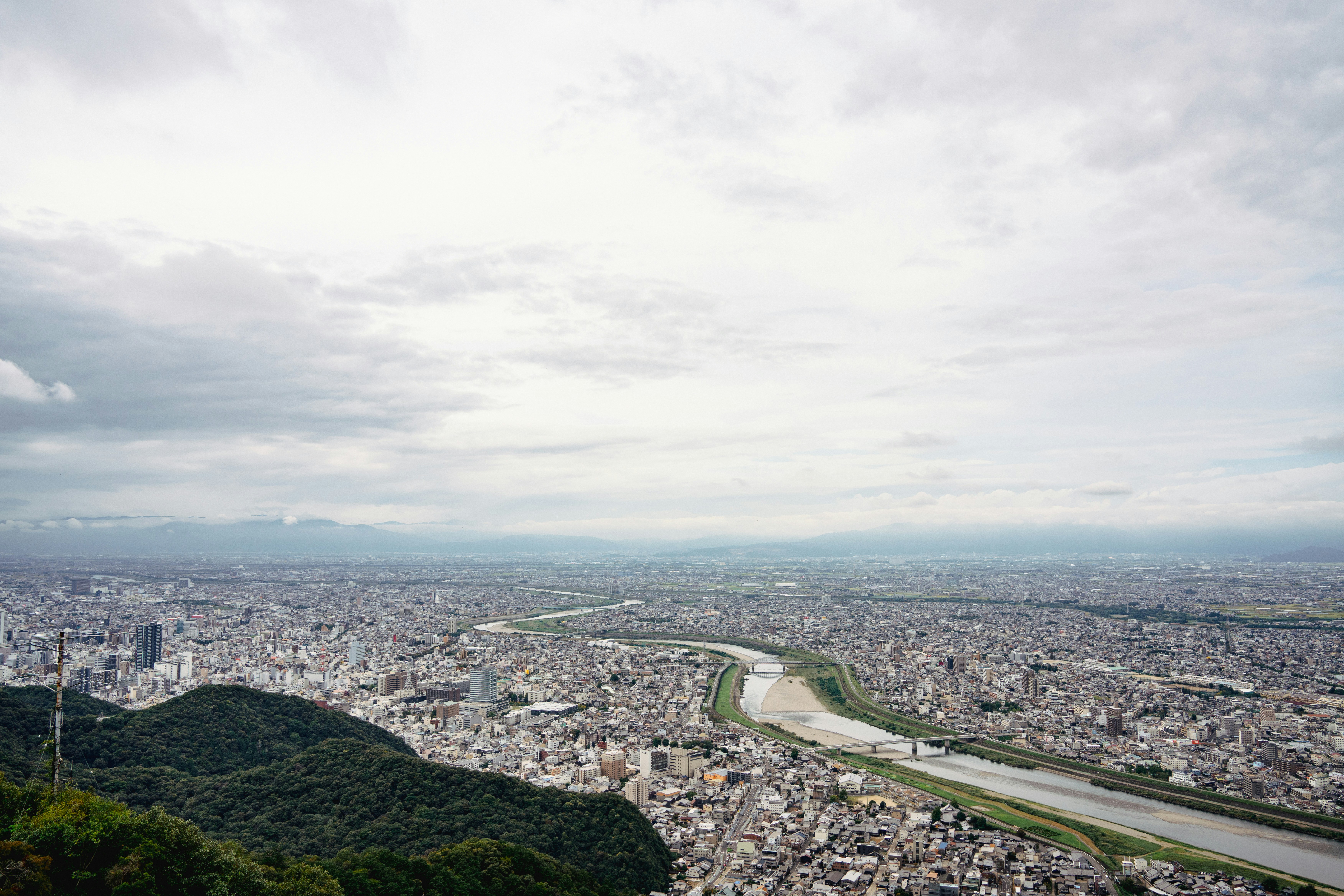 Cityscape with a river flowing through it under cloudy sky.