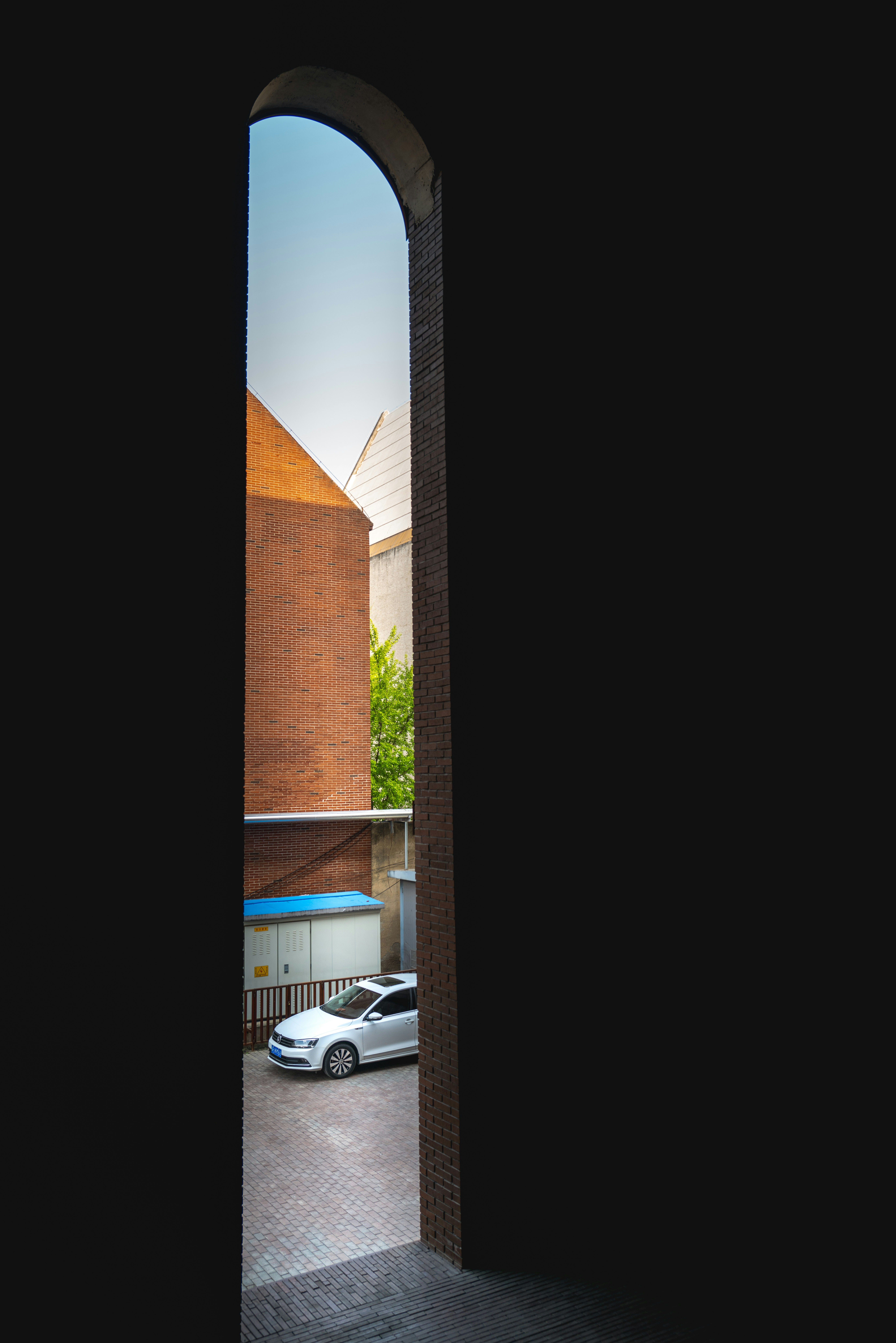 Through the Arch: a Quiet Urban Courtyard Reveals a Silver Car