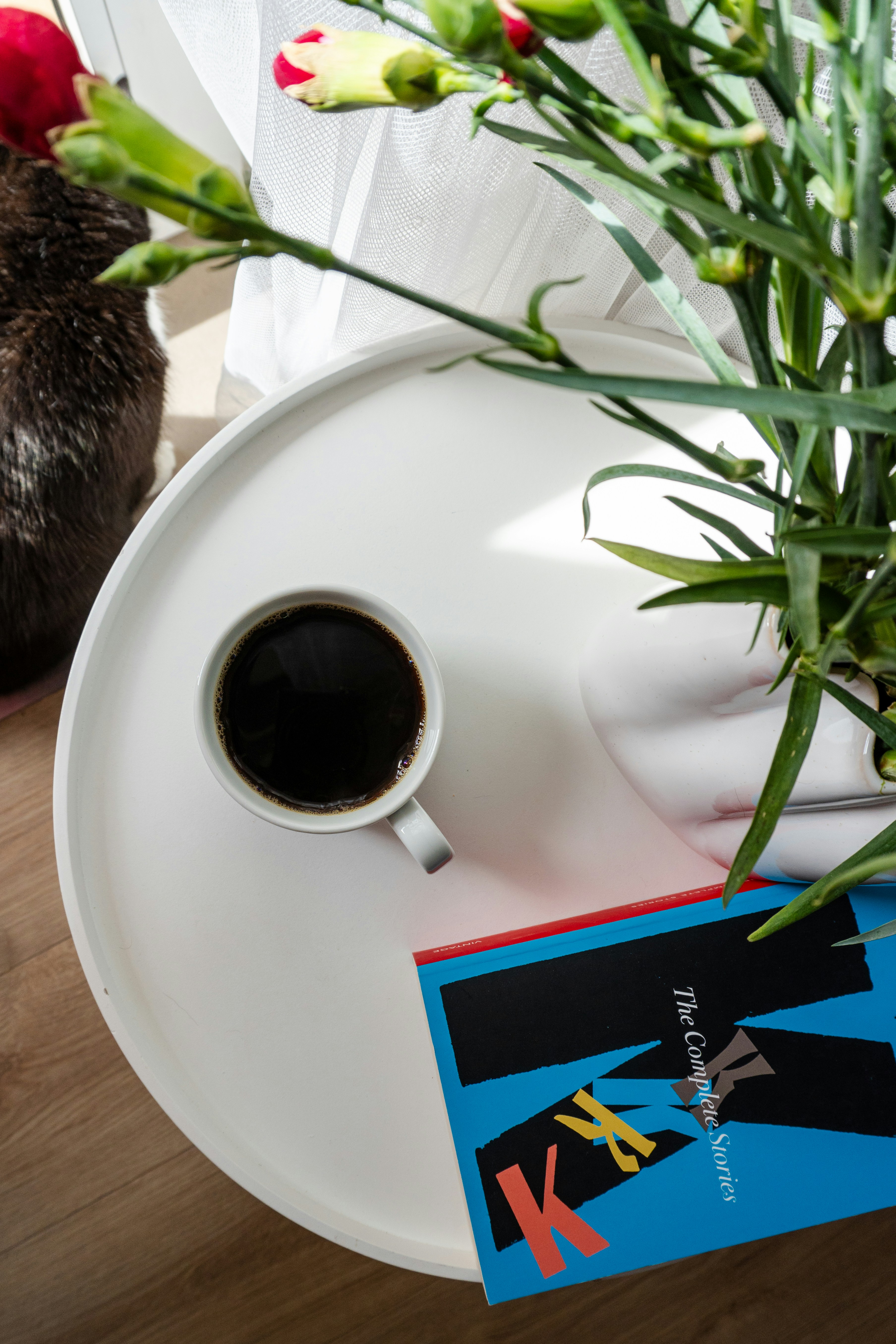 Coffee on White: A Quiet Moment with Flowers and a Booklet
