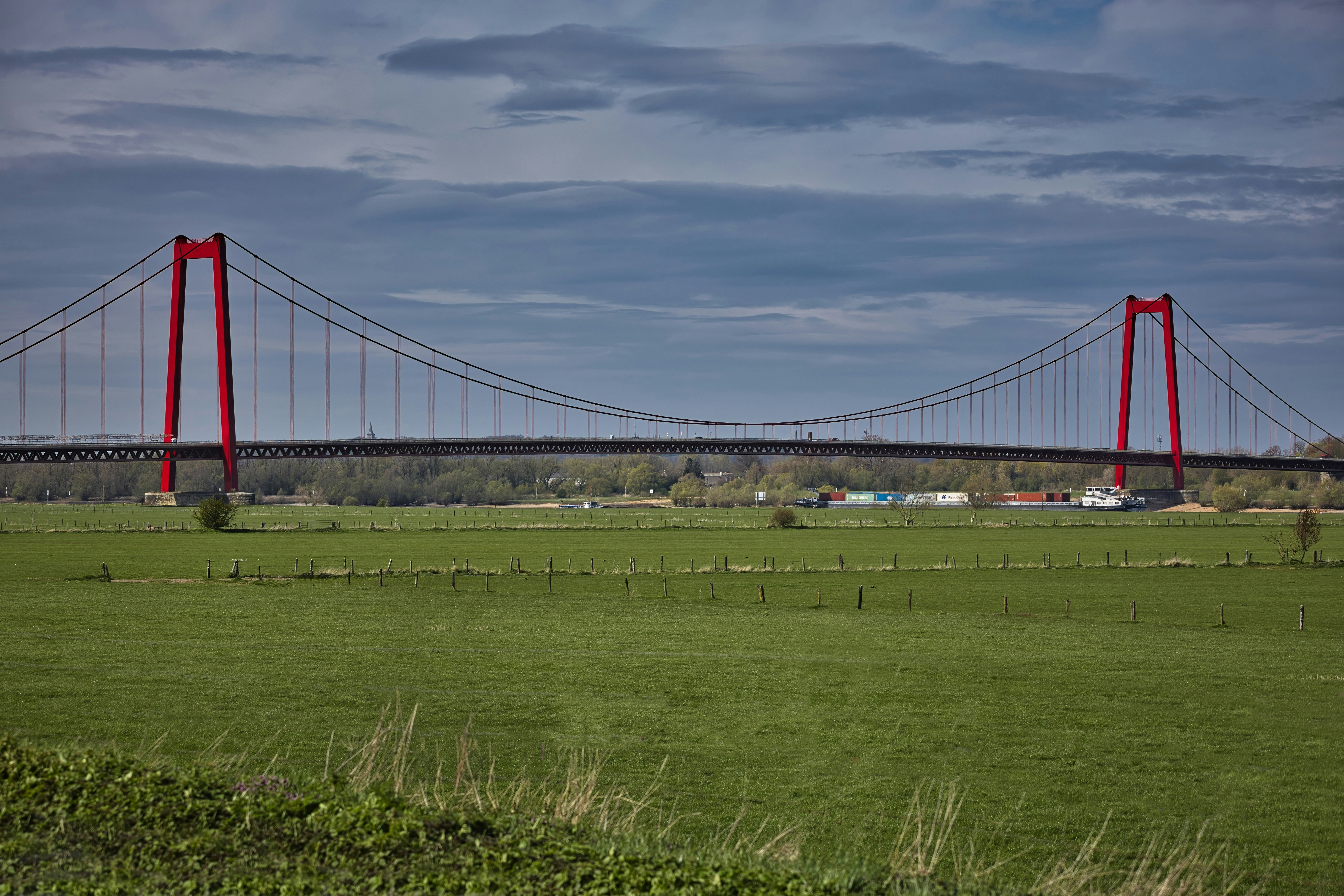 Red Suspension Arches Crossing a Quiet Field