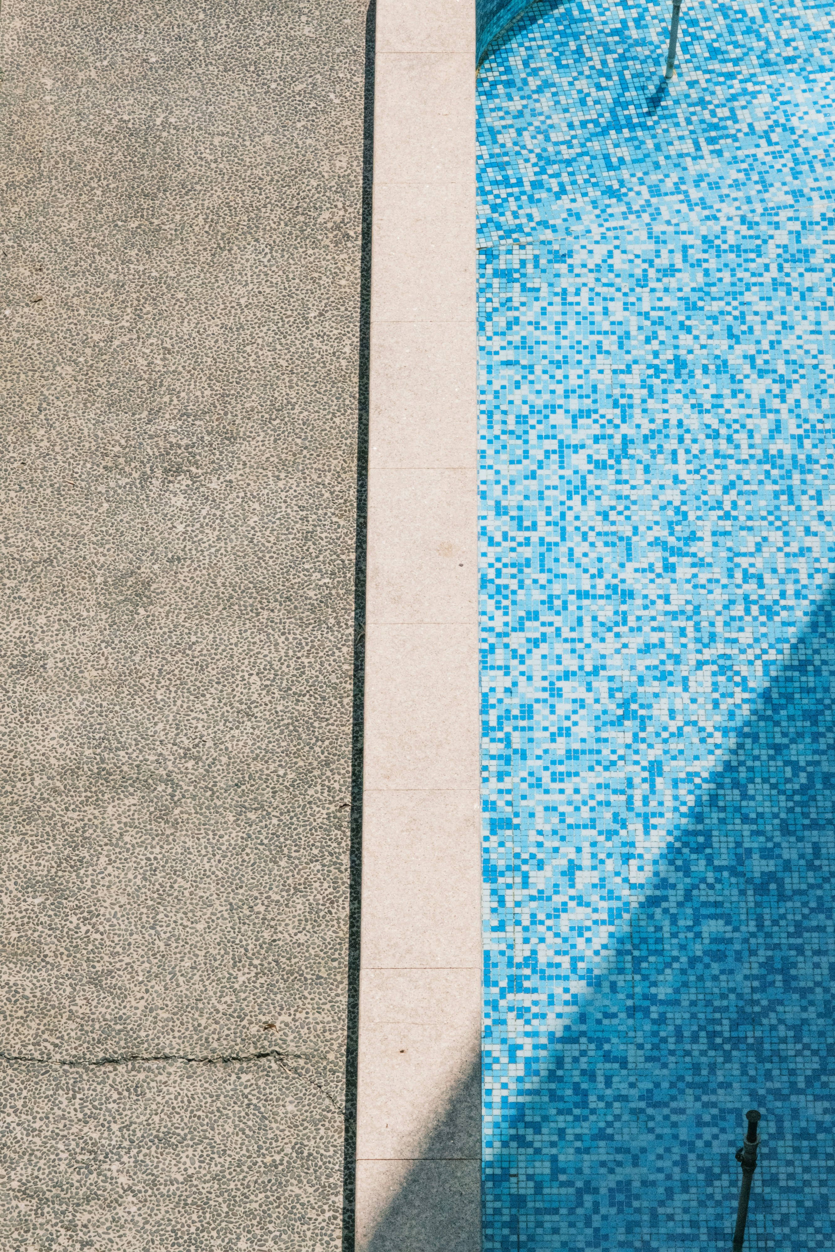 Edge of Aqua Mosaic: A Sharp Divide Between Pool Ink and Pool Deck