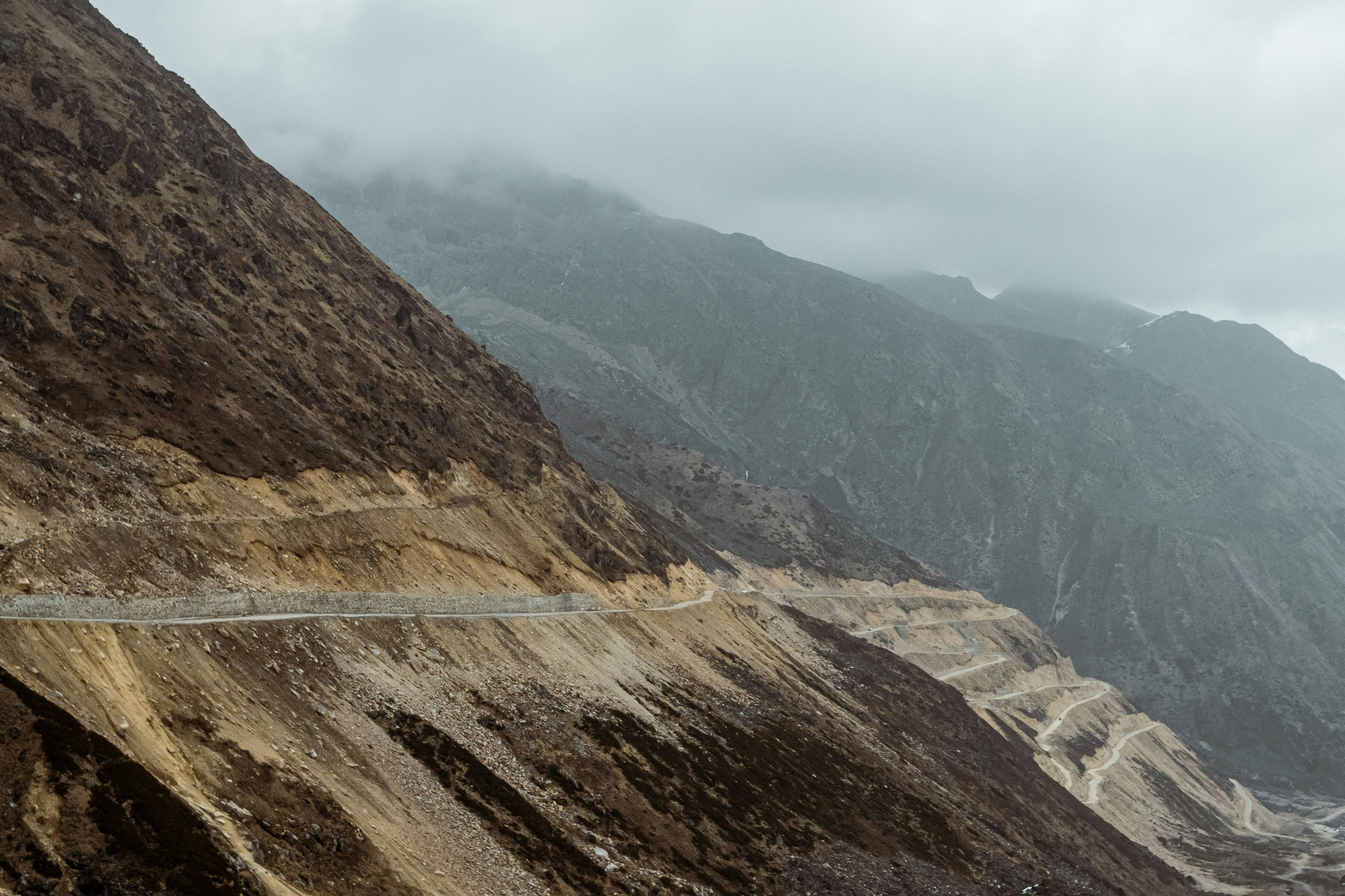 Winding Mountain Pass: A Rugged Road Carves Through Misty Stone