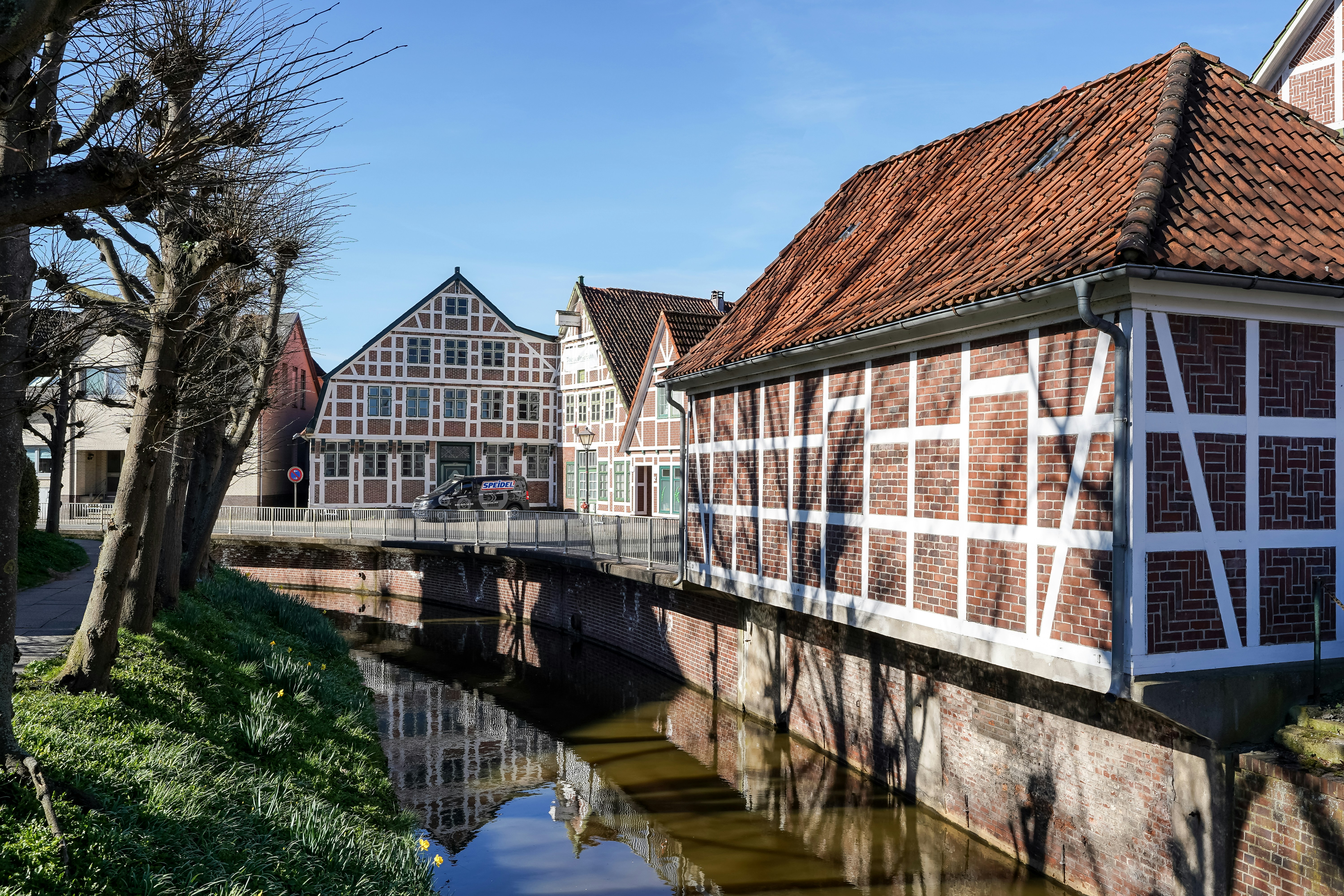 Timber-framed row by the canal: a sunlit Flemish-inspired street