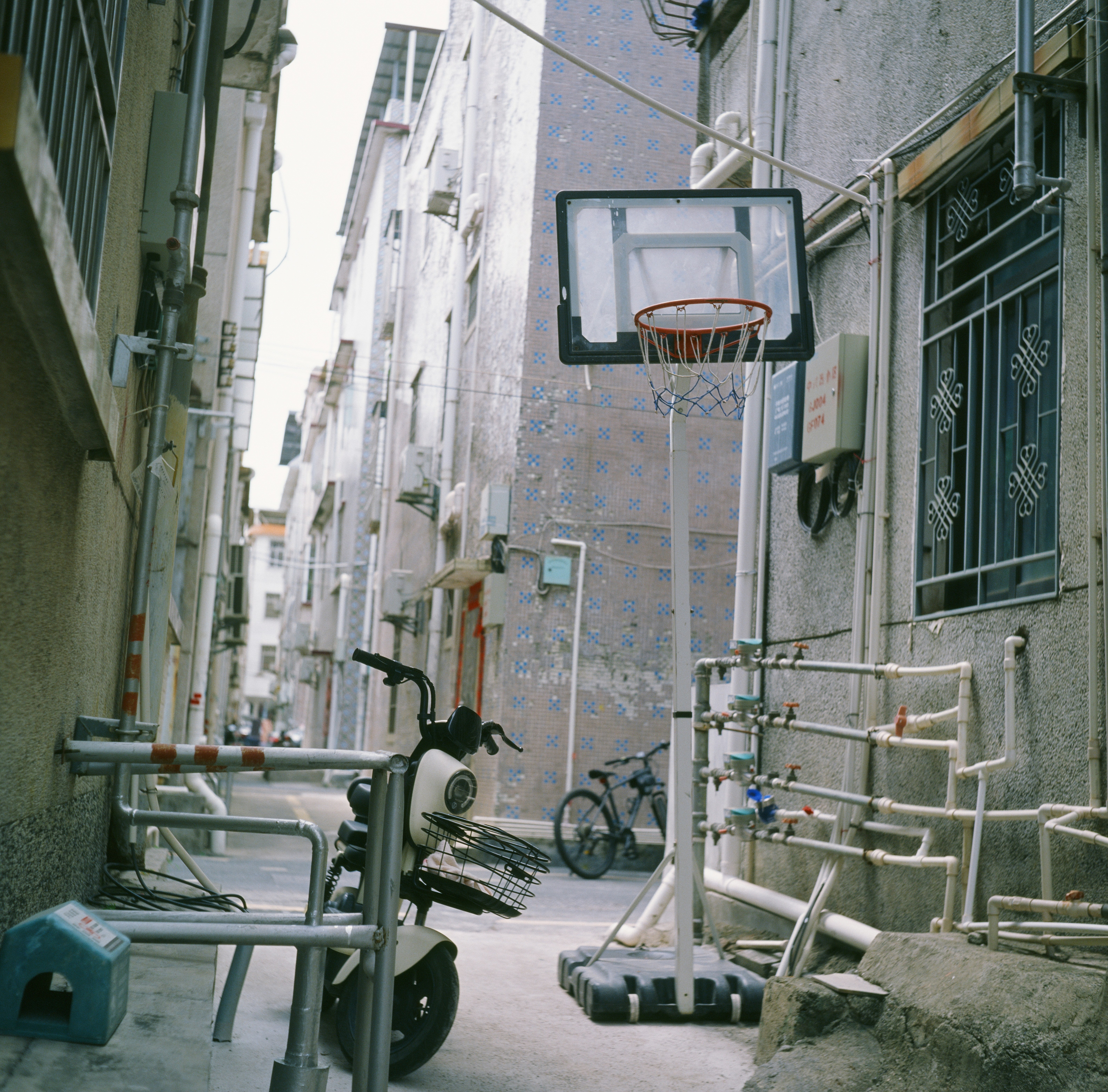 Basketball Court in a Quiet Alley: A Bicycle and Hoop View