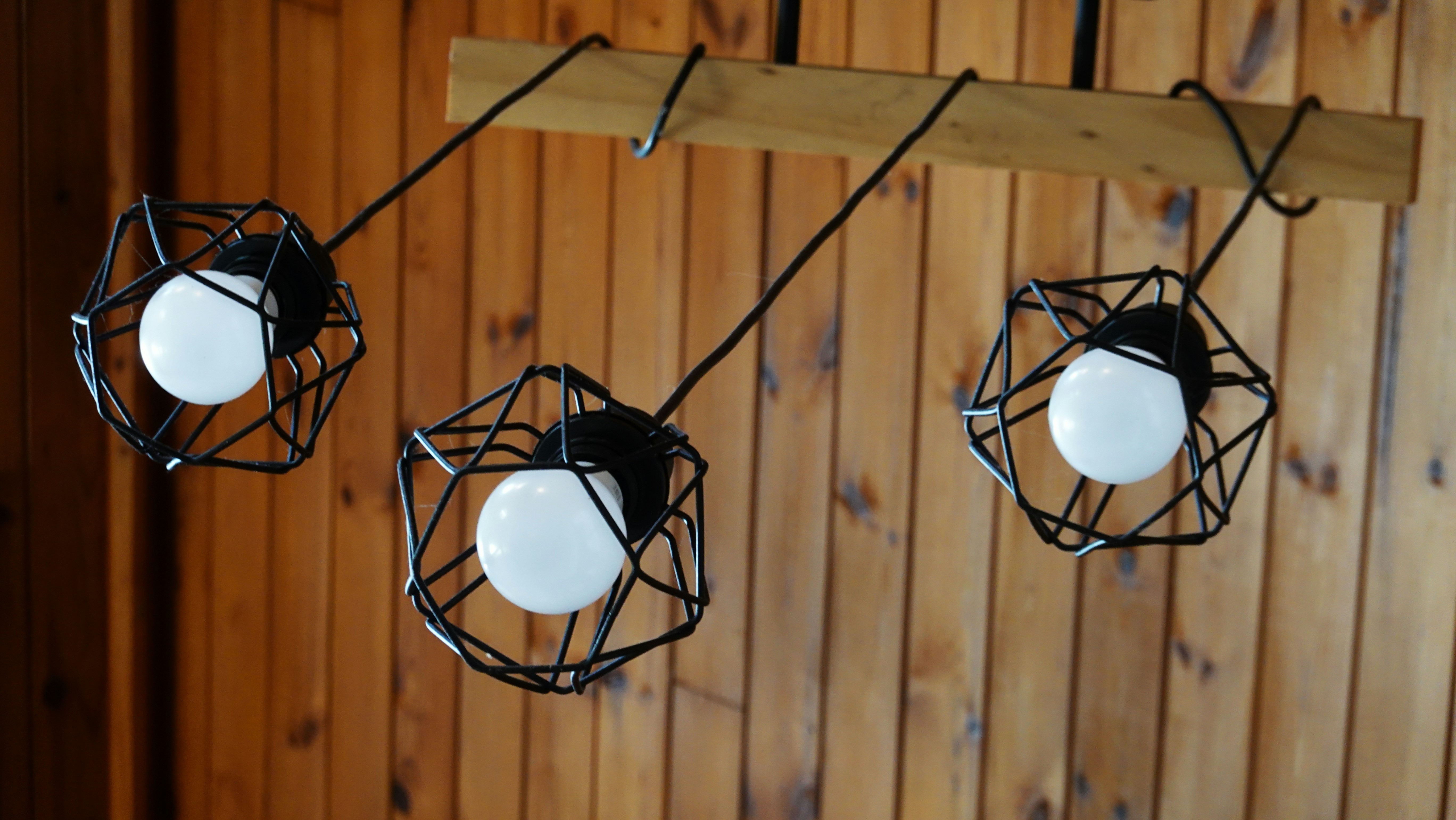 Geometric Warmth: Trio of Wire-Frame Lamps Casting Soft Orb Light