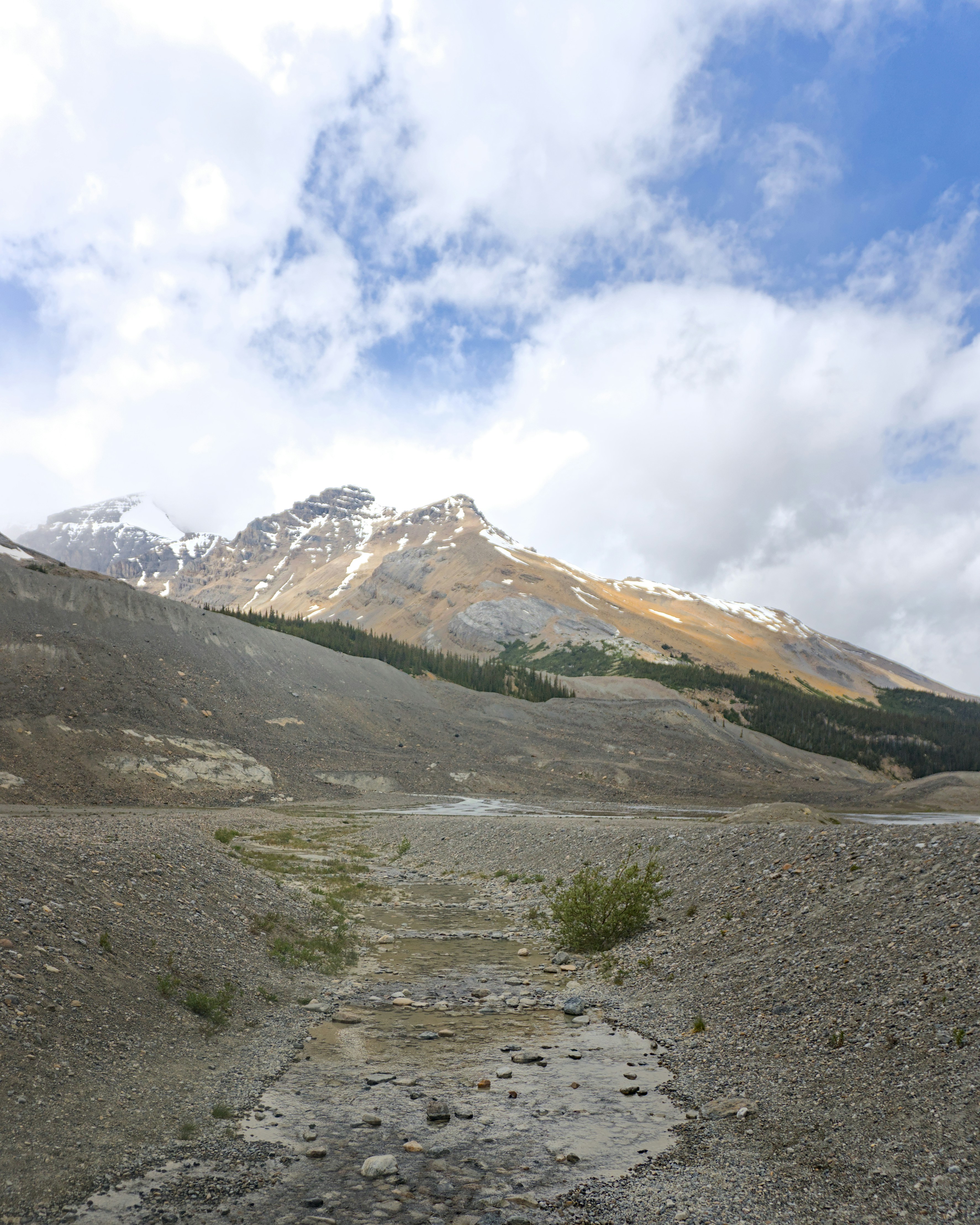 Rocky landscape with a stream and snow-capped mountains