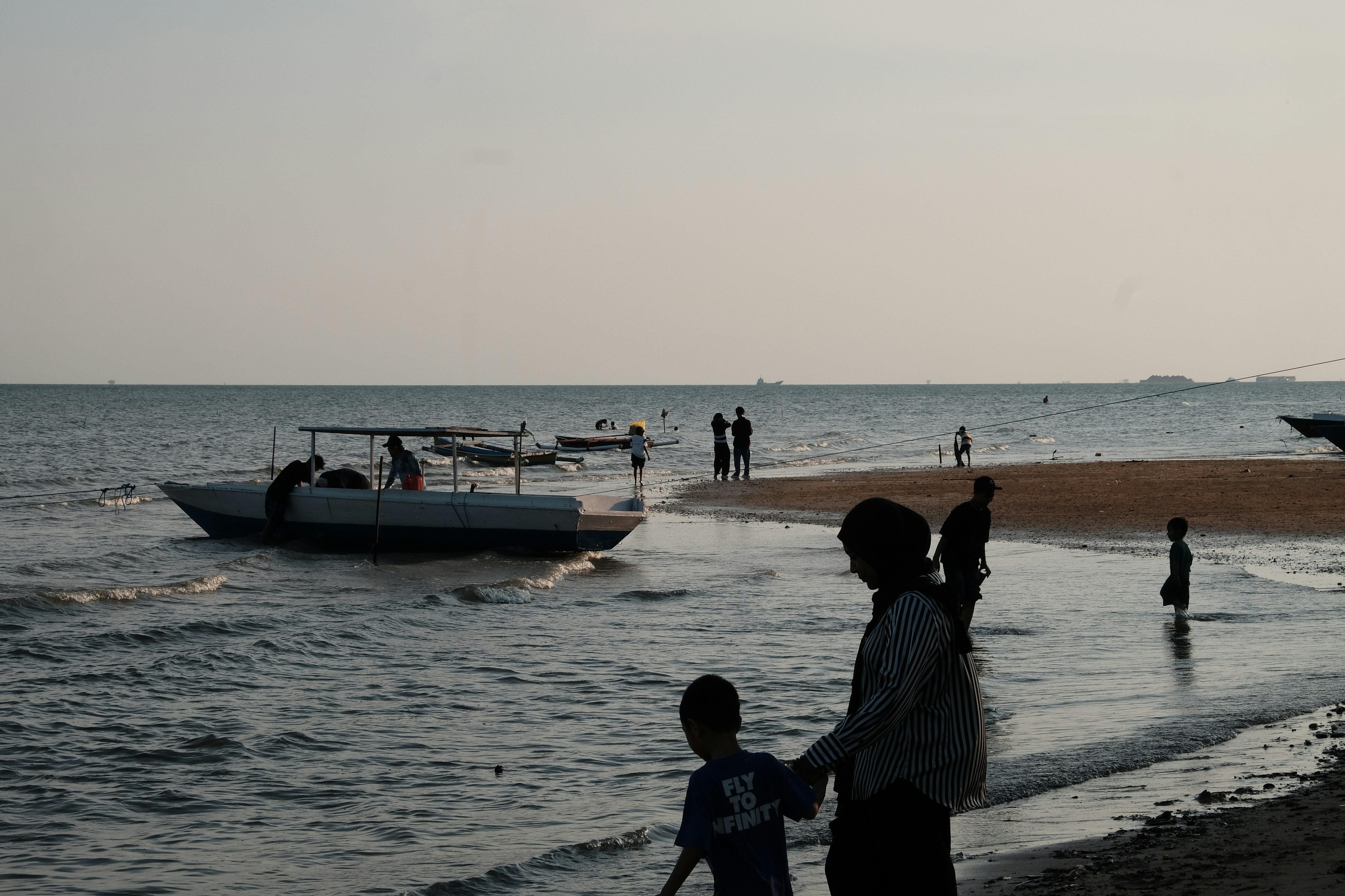 Silhouettes at the Shore: Distant Boats and a Quiet Beach