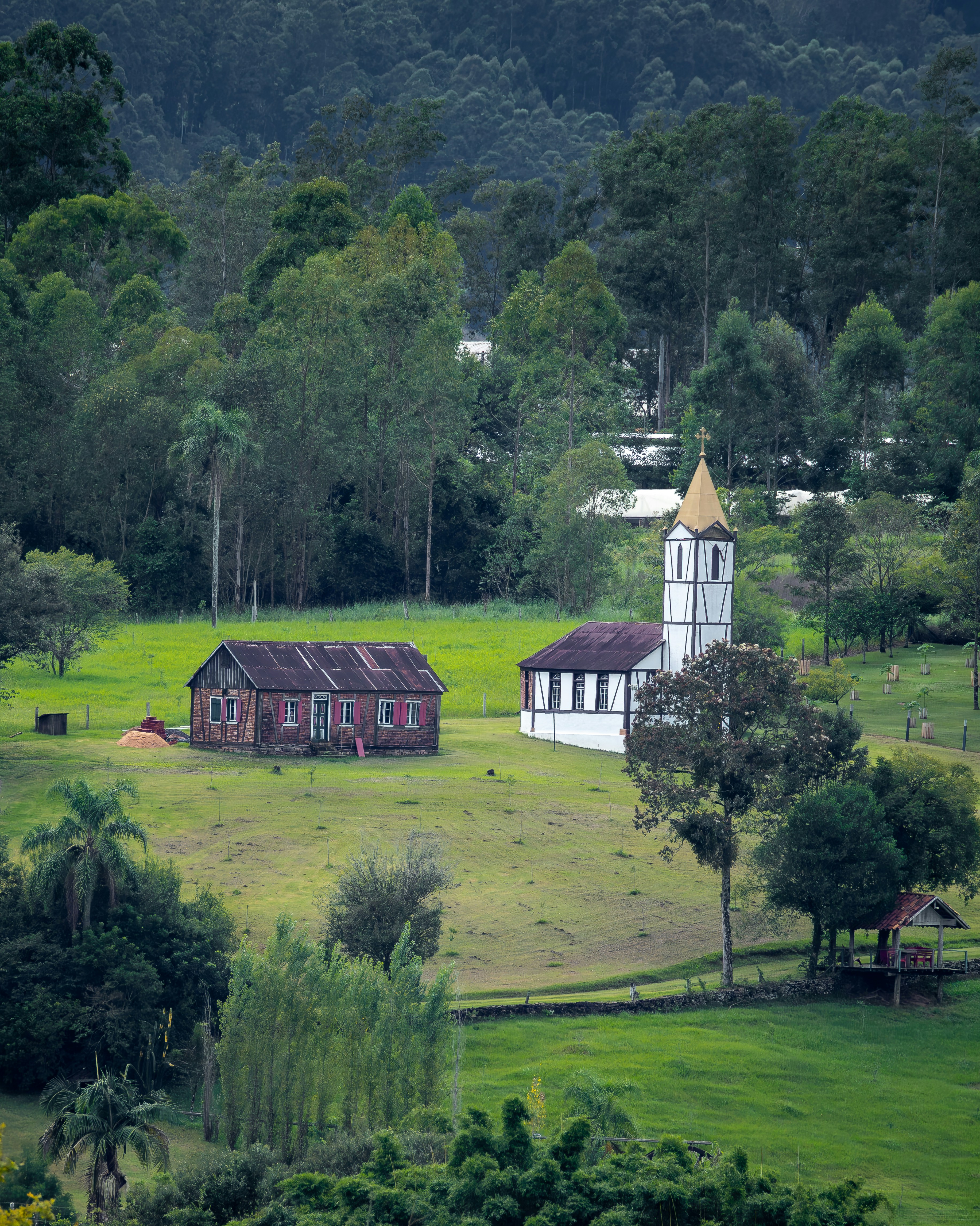 Quiet Countryside Chapel and Barn Beneath a Verdant Sky