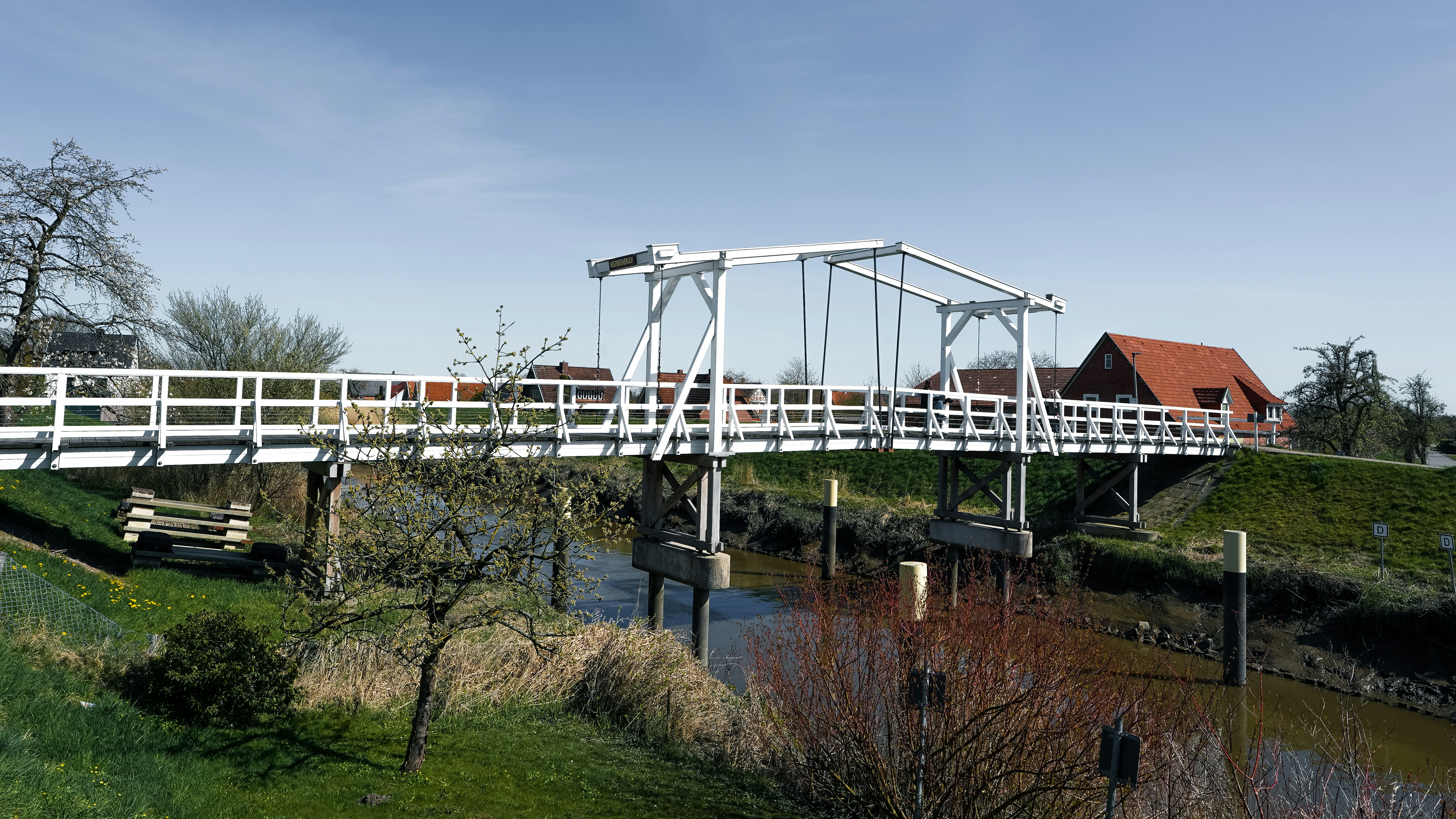 White-p serviced drawbridge over a tranquil river under a clear sky