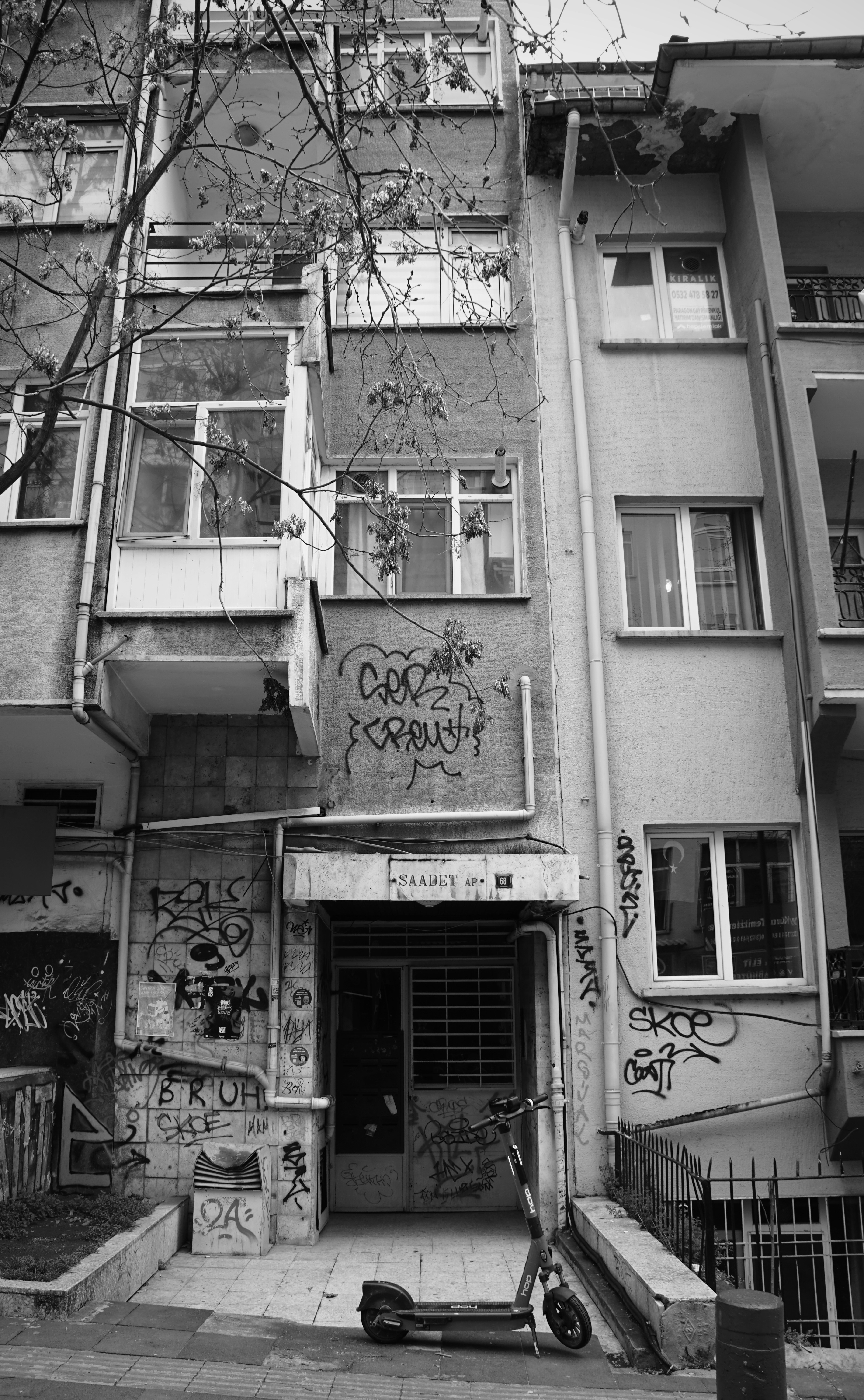 Urban doorway beneath graffiti-laden facade with an electric scooter at the threshold
