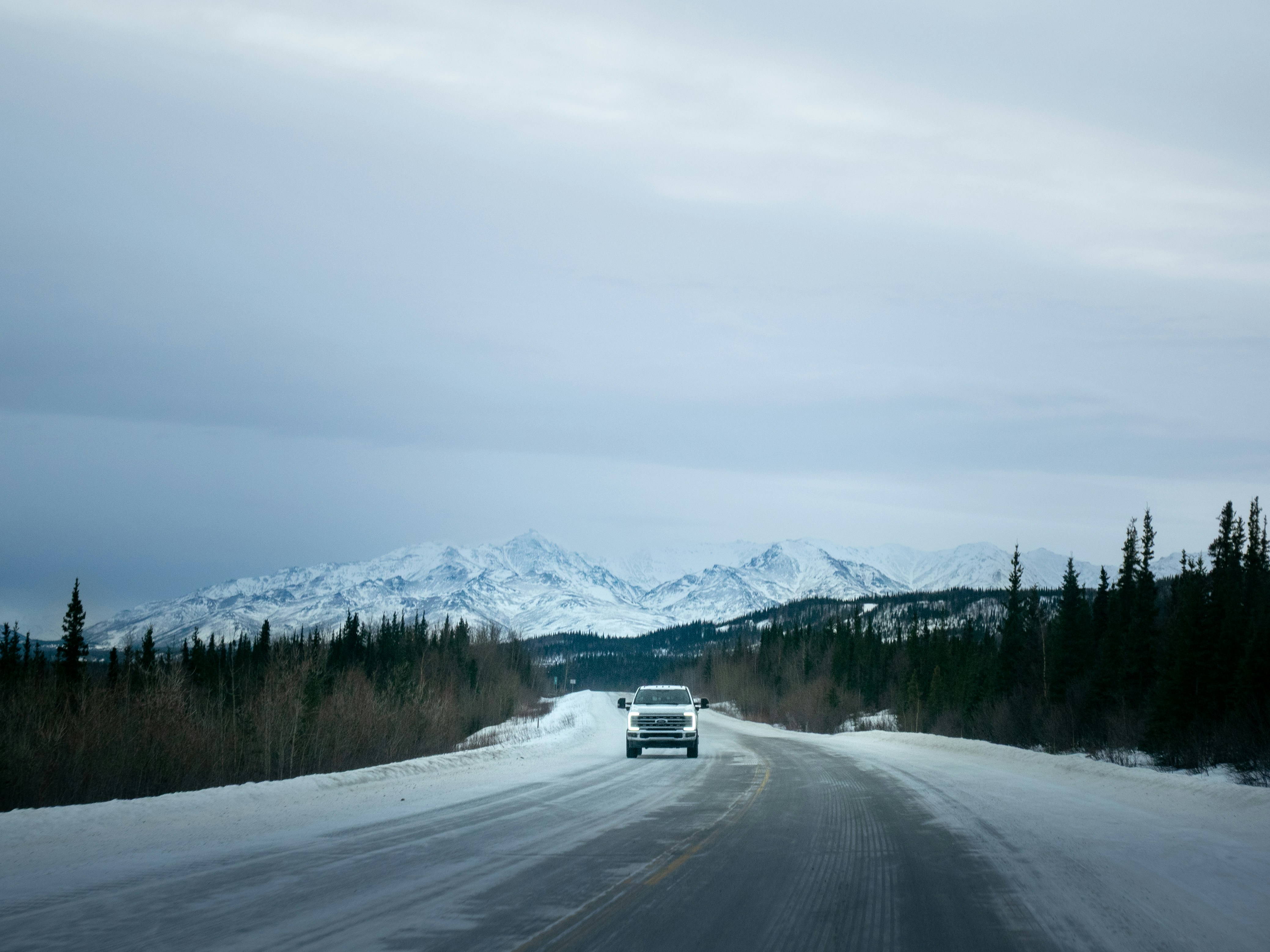 Snowbound Highway: A Lone Vehicle Traverses a Quiet Alpenglow