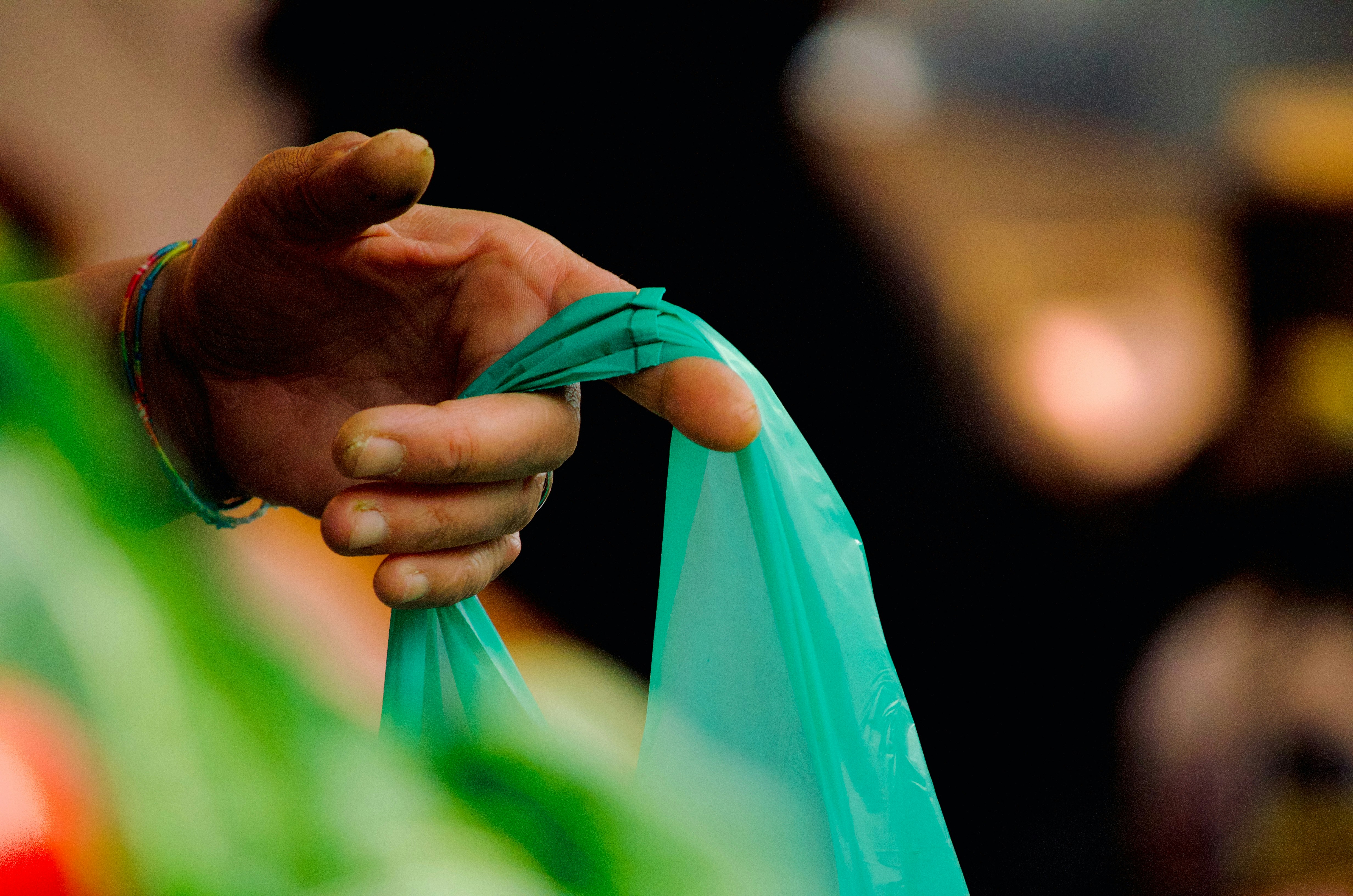 Green plastic bag held by a hand in a soft-lit scene