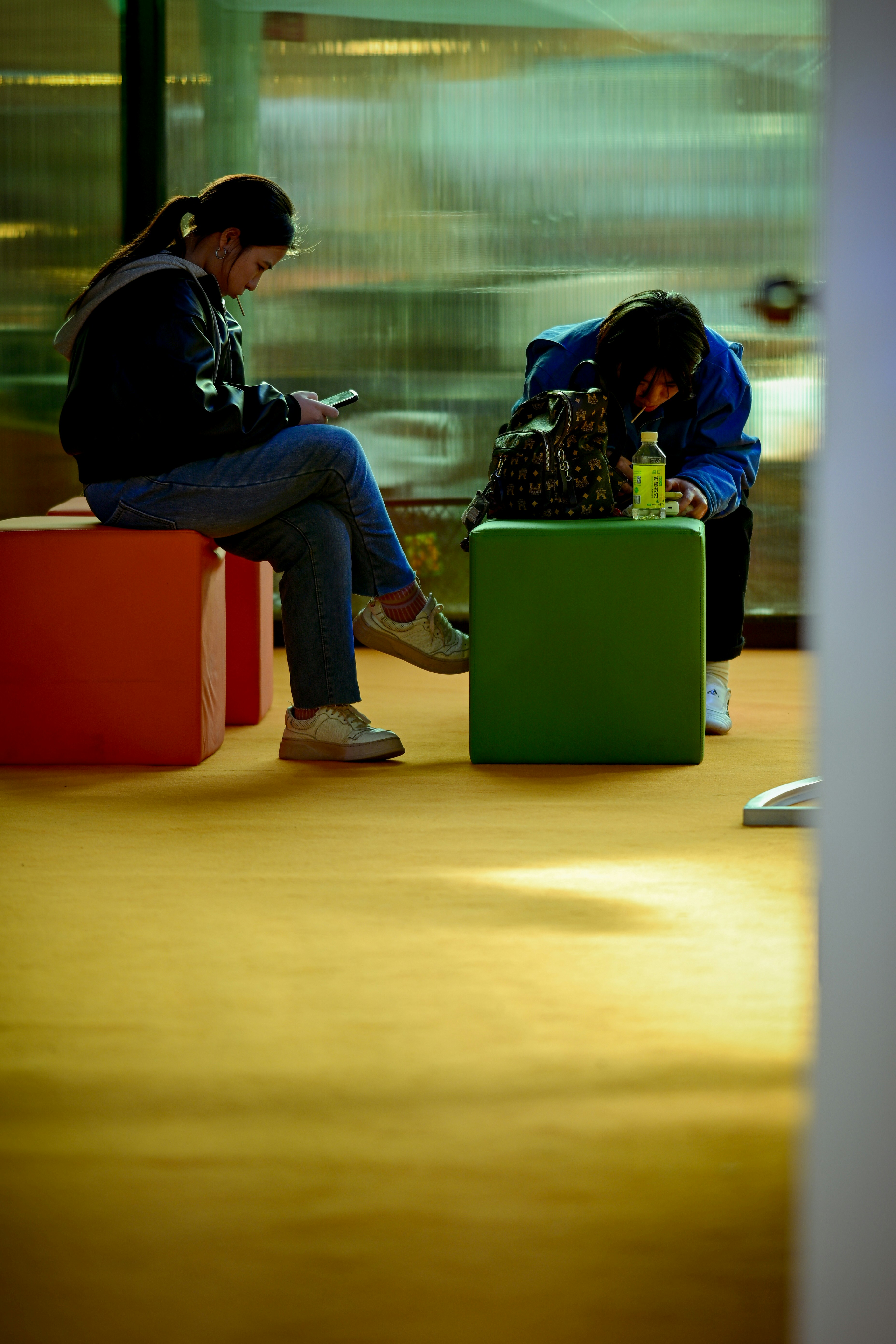 Quiet Pause: Two Travelers in Conversation Amid Colorful Seating