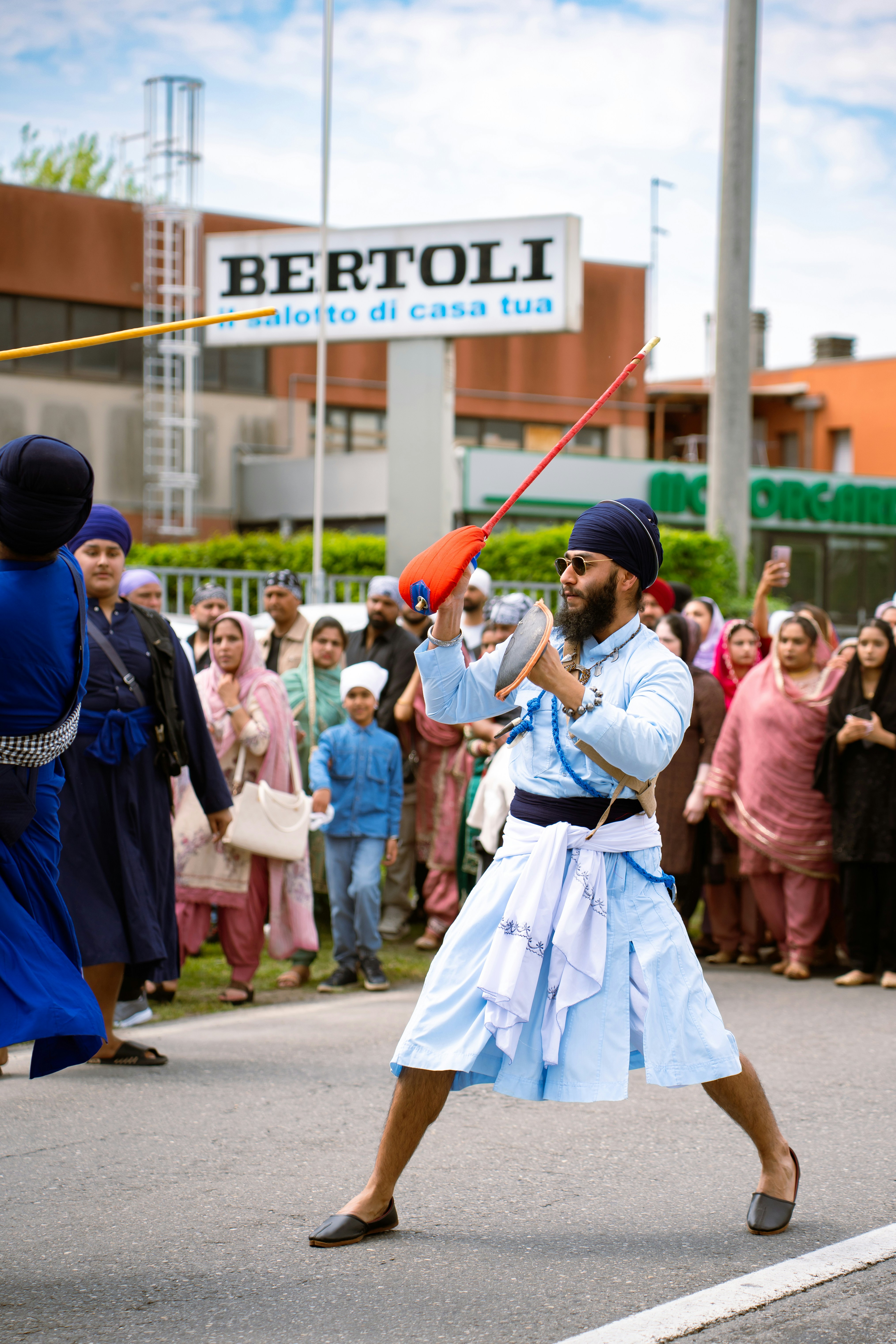 Sikh swordsman in motion amid cheering crowd at a street festival