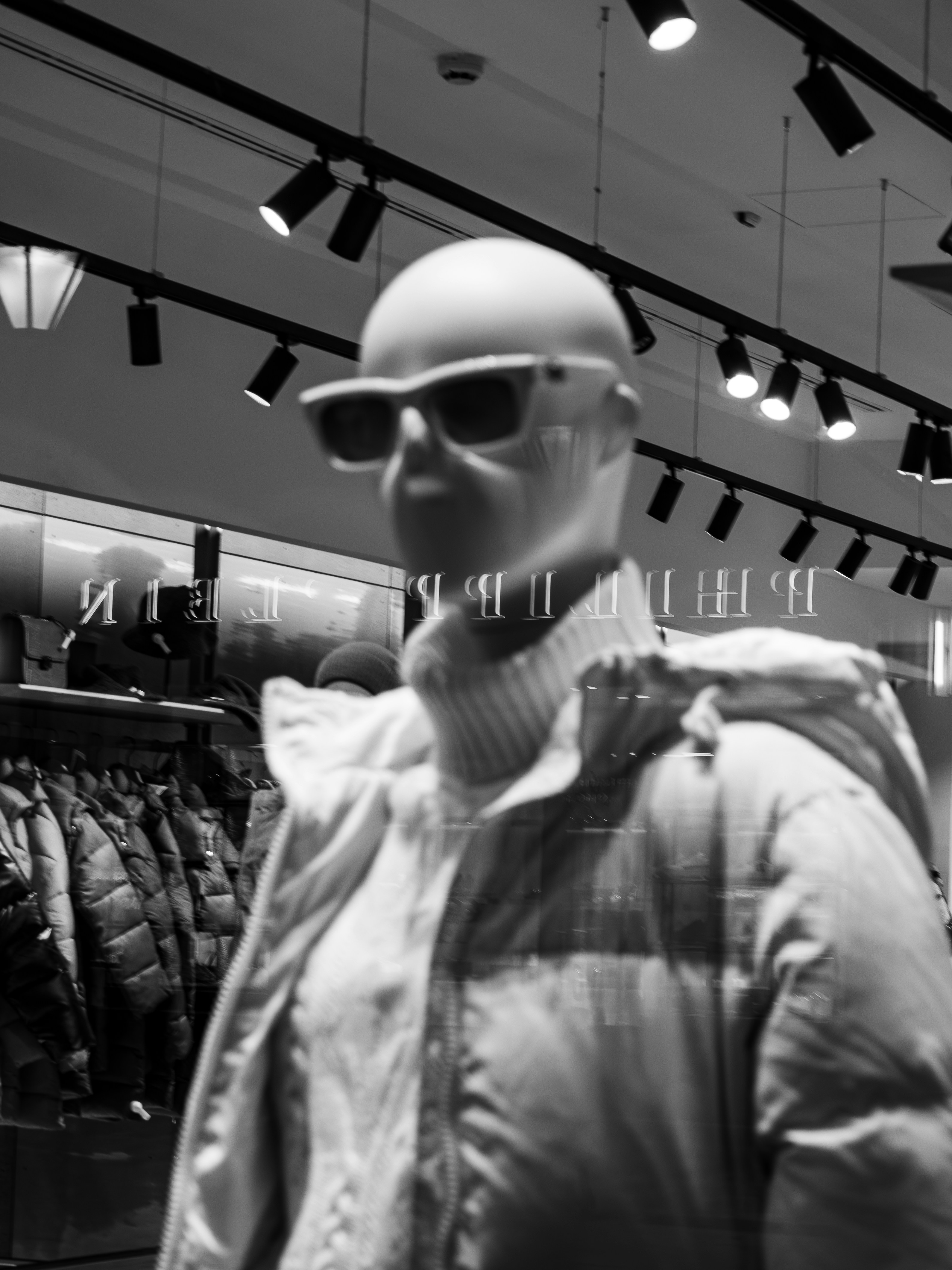 Blurred mannequin, storefront glow: ice-cold reflection in a glassy display