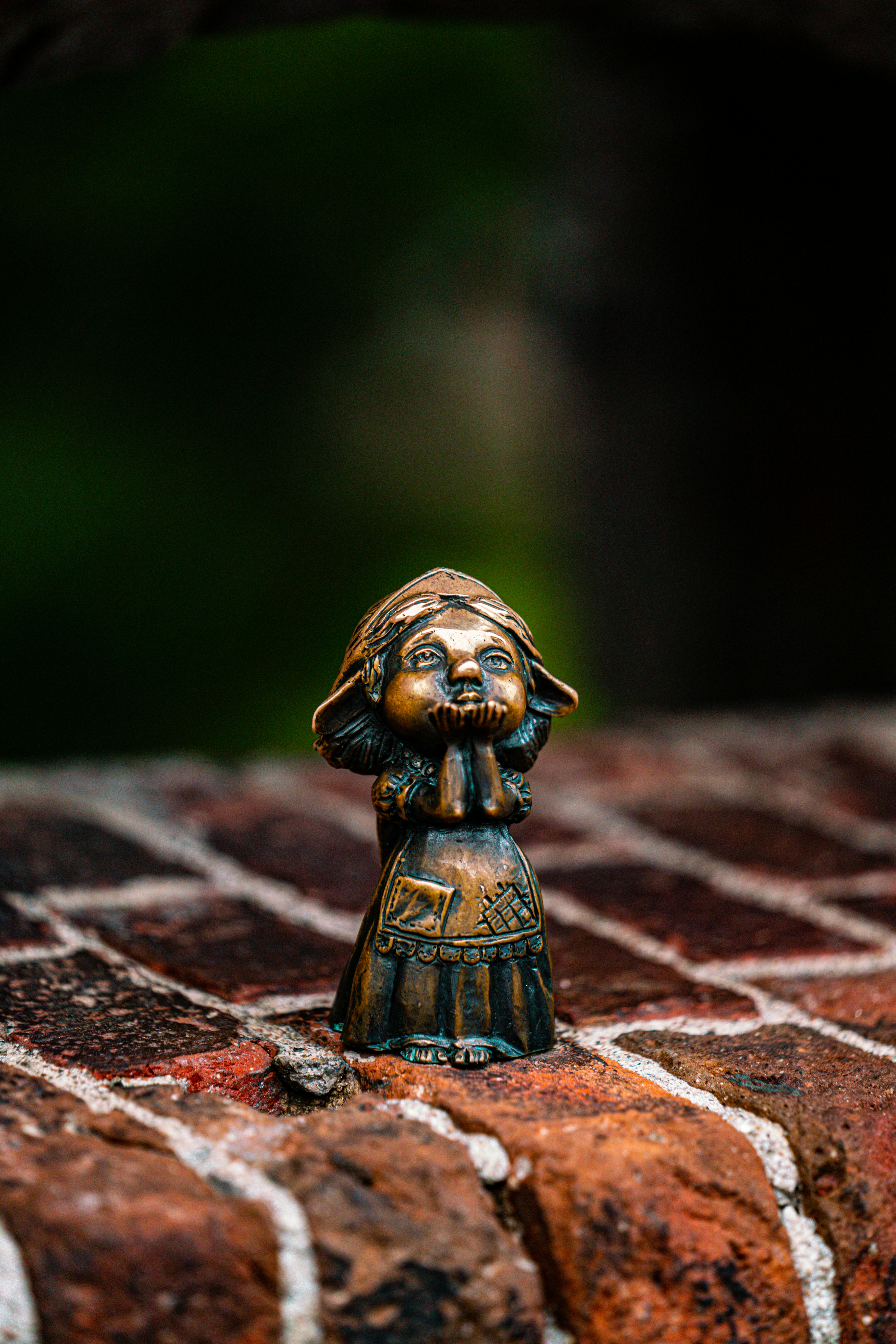 Bronze Child Figure on Weathered Brick Wall