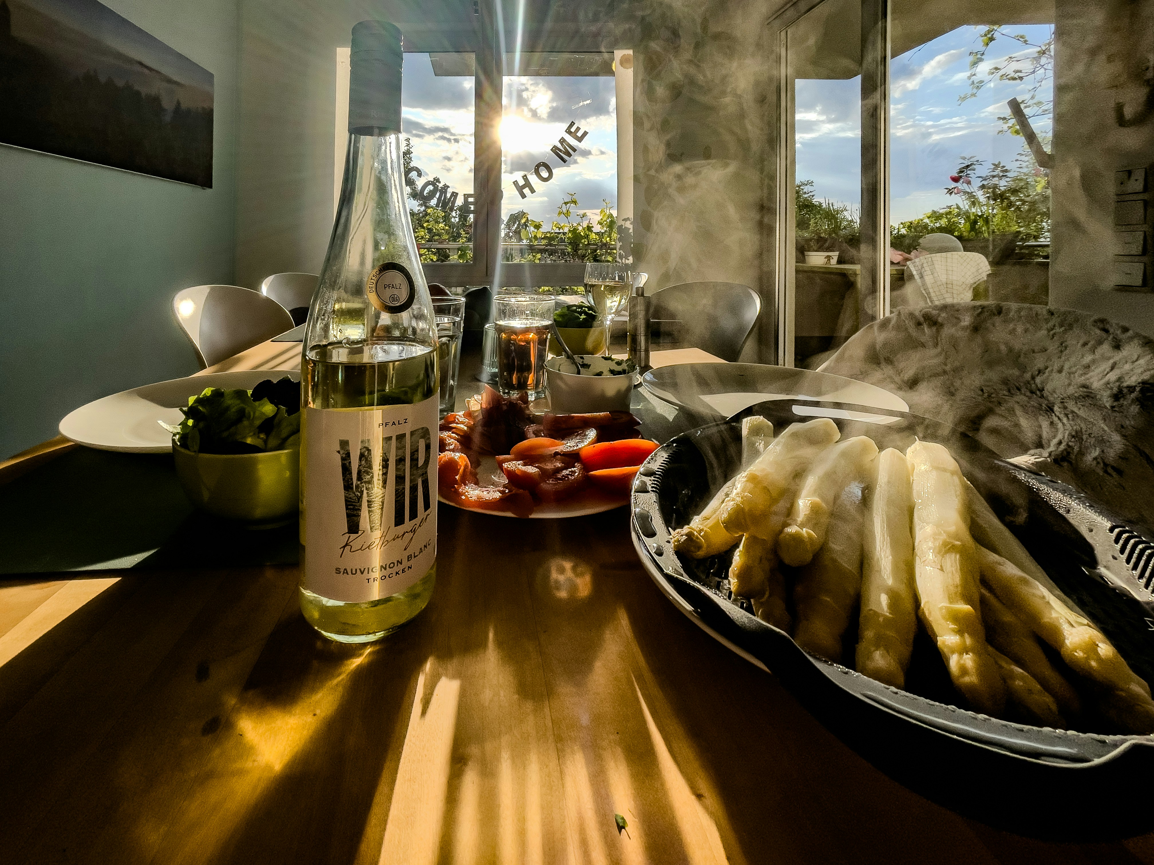 Sunlit Feast: Sausages, Bread, and Greens Steam in a Warm Kitchen Table