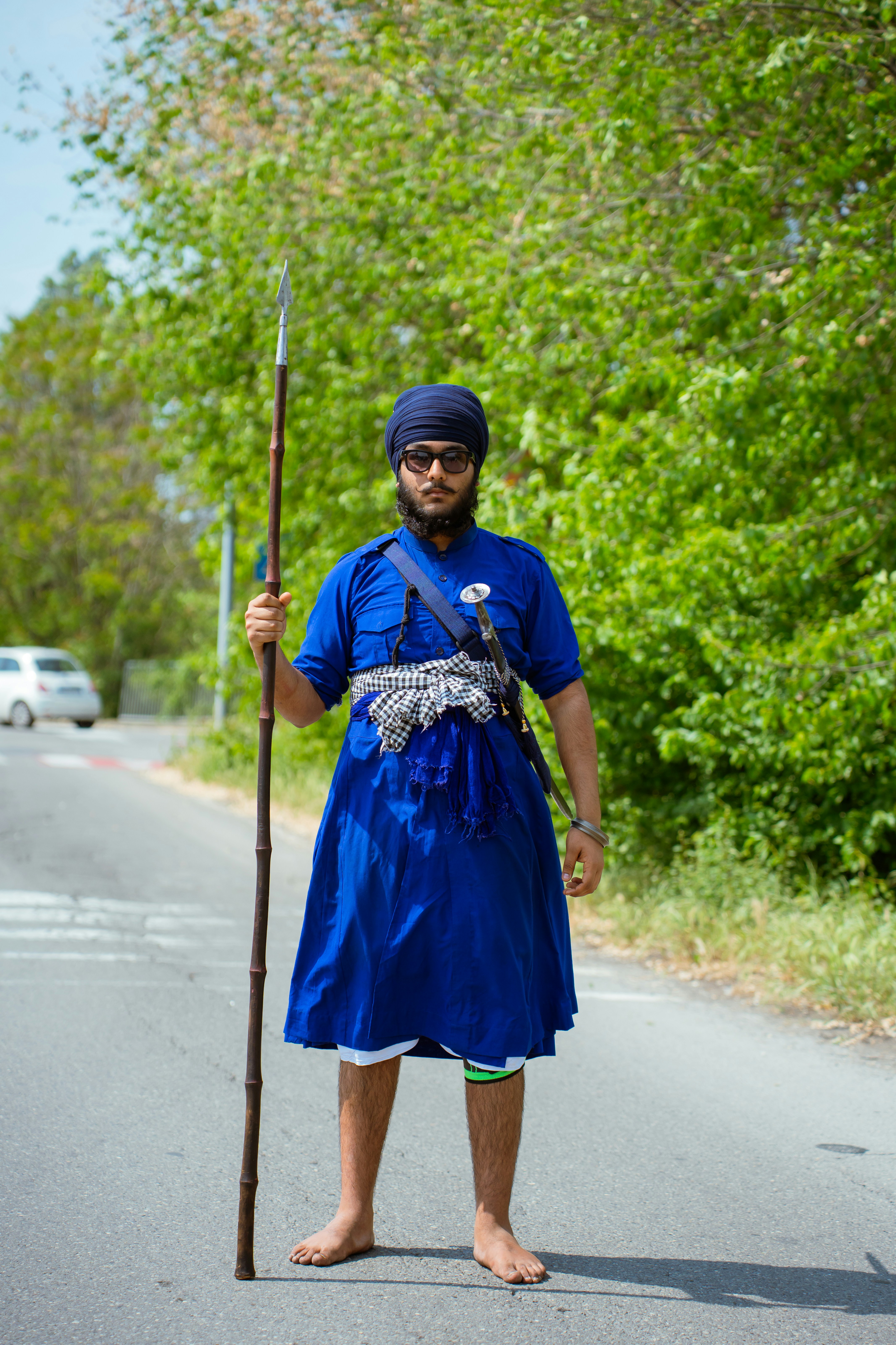 Blue robe under the streetlight: a barefoot guardian with a spear