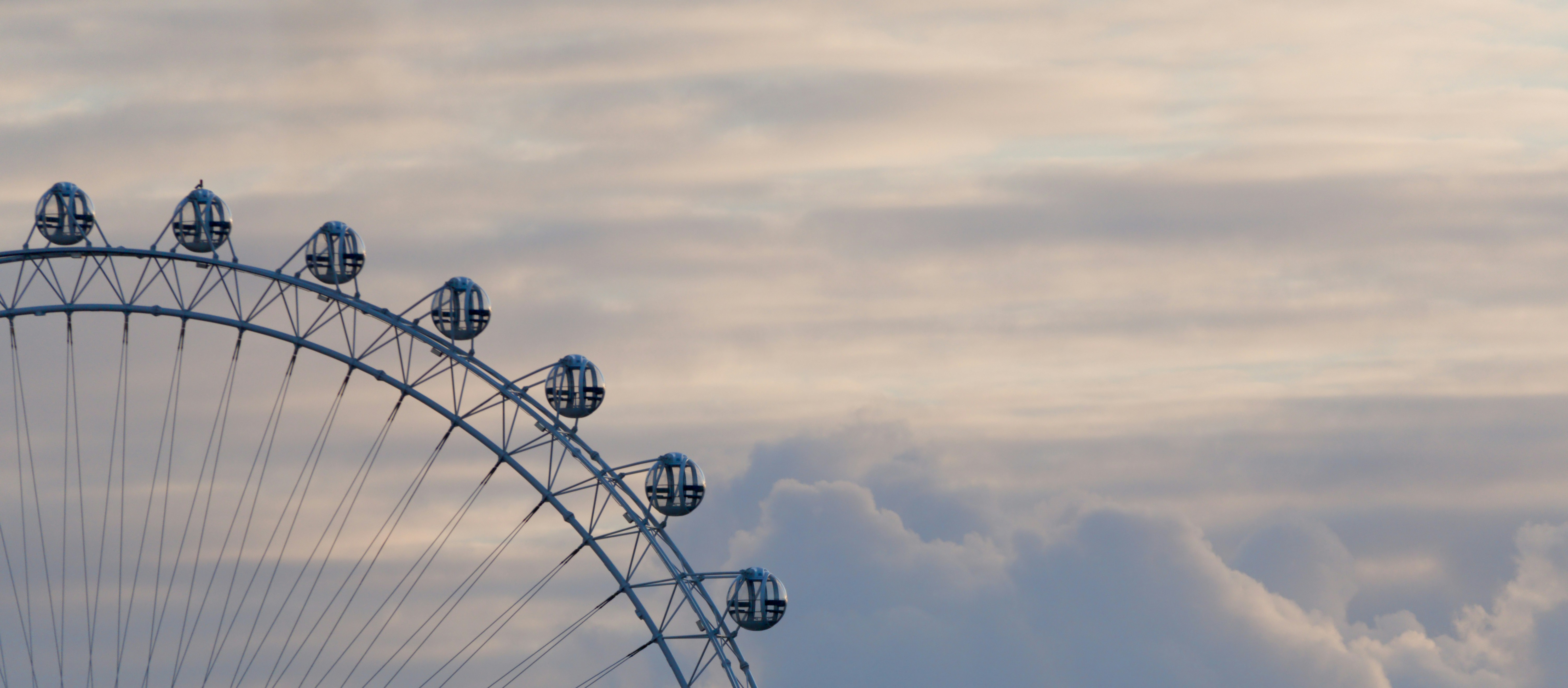 Ferris Wheel Arc: a sliver of motion against a clouded sky