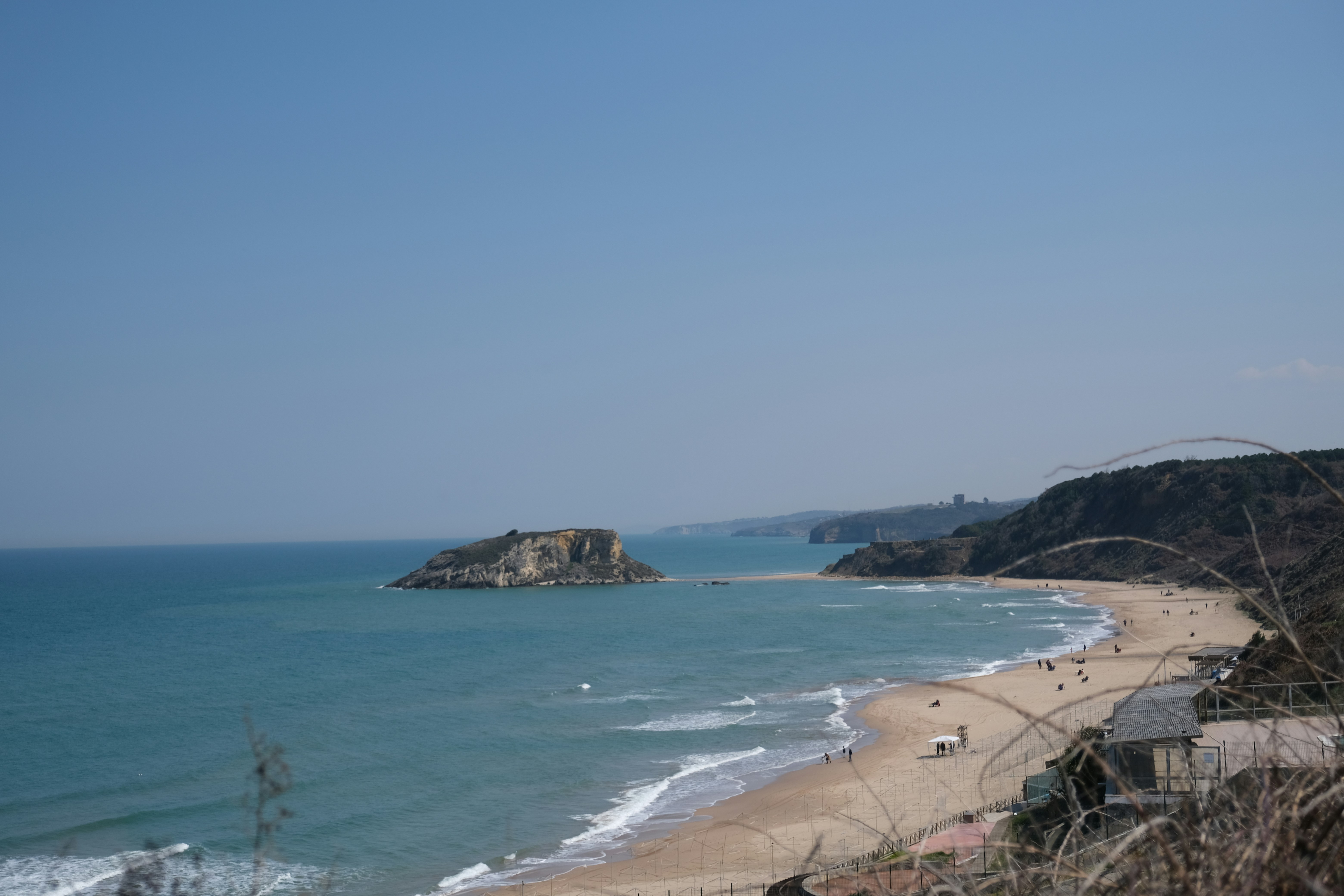 Coastal Curve: Quiet Beach Under a Clear Sky