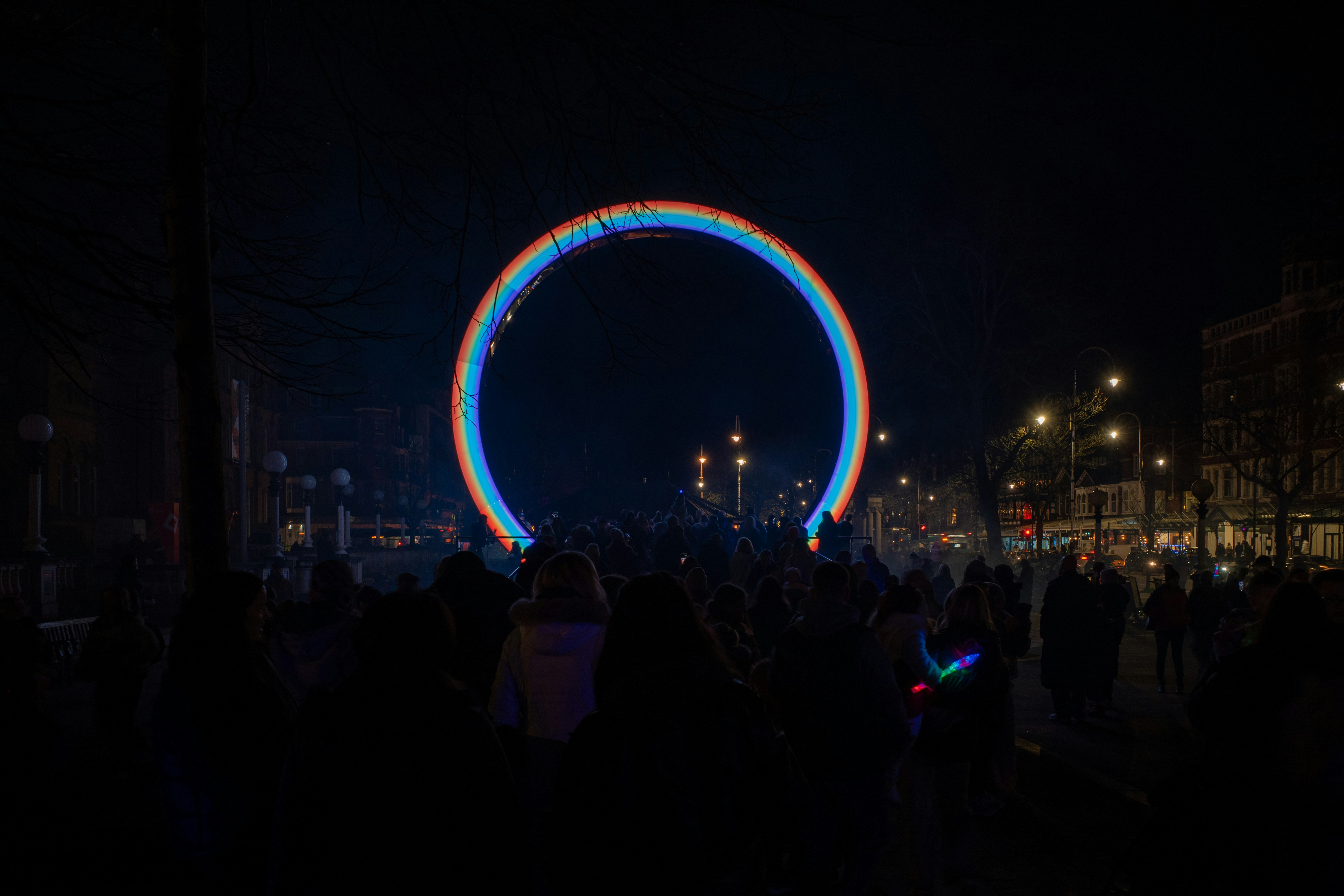 Neon Ring Above a Crowd: Light Sculpture at Night