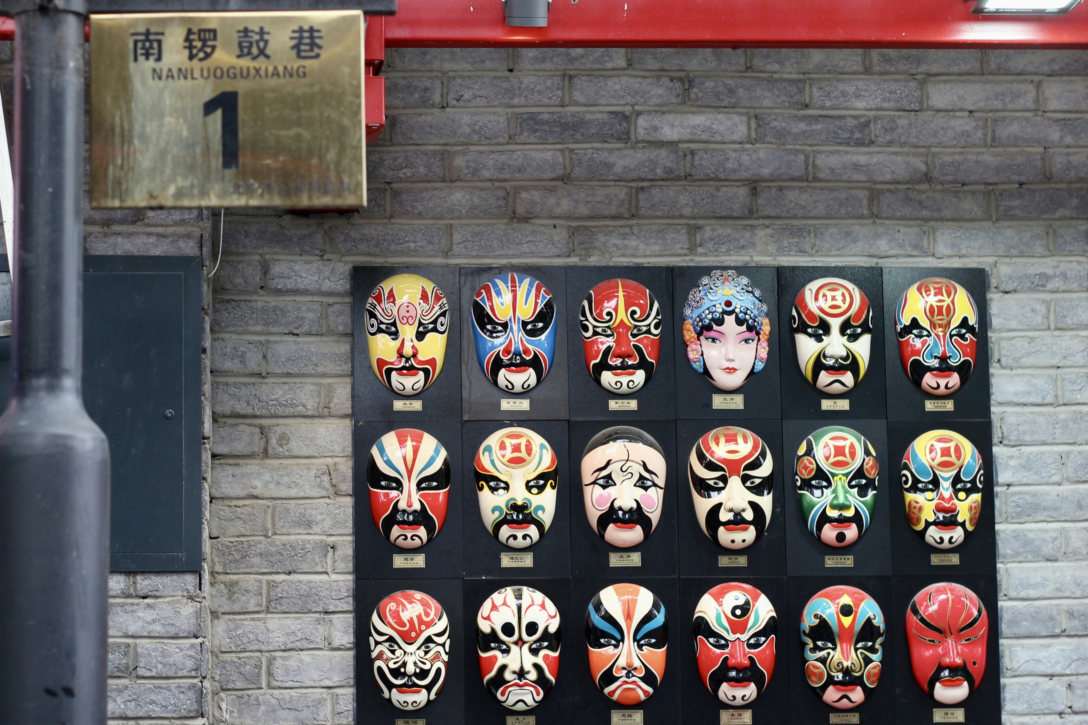 Masks on the Brick Wall: A Street Shrine of Colorful Faces