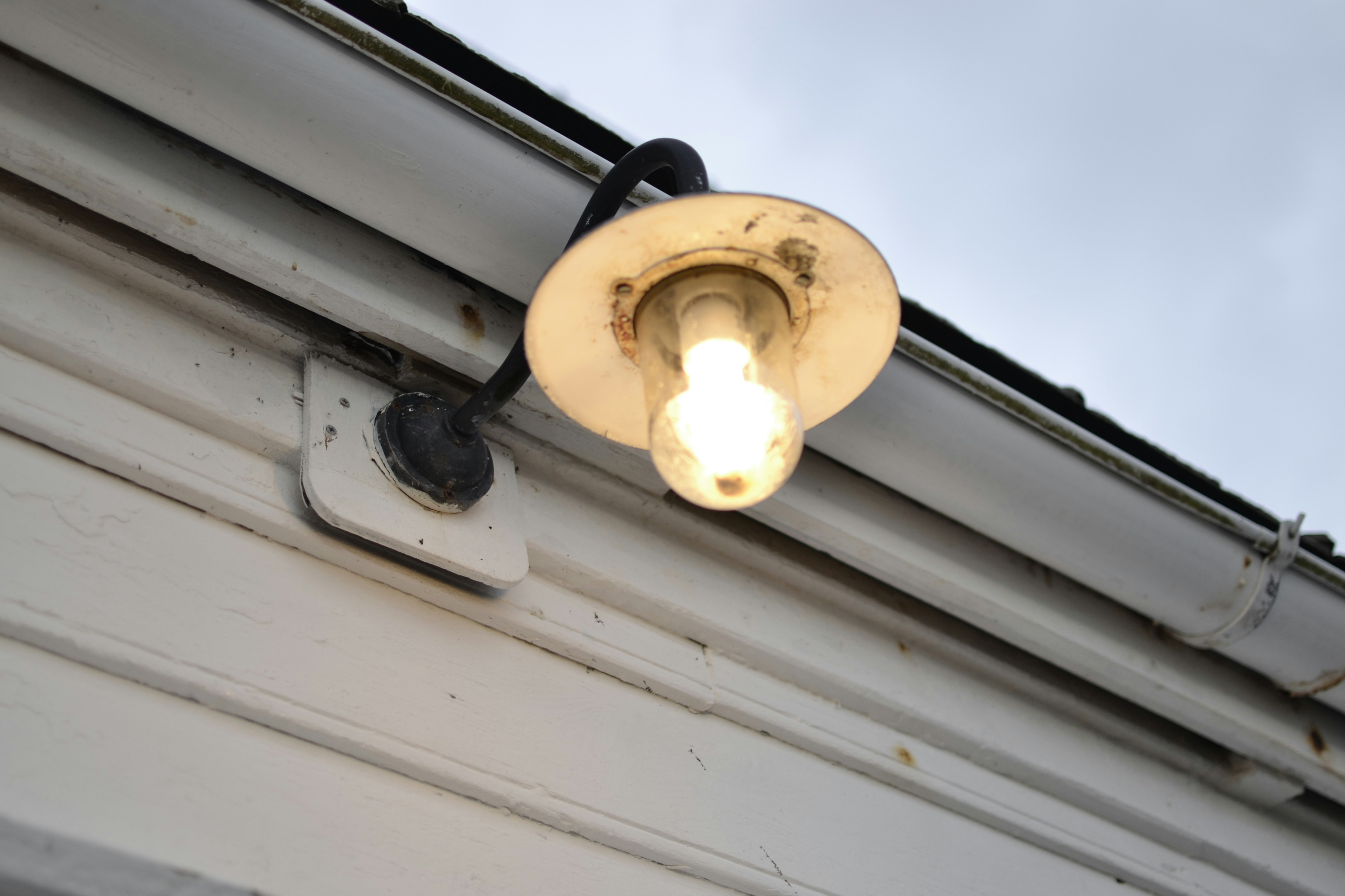 Aging Exterior Light Bulb on a Rustic White Siding