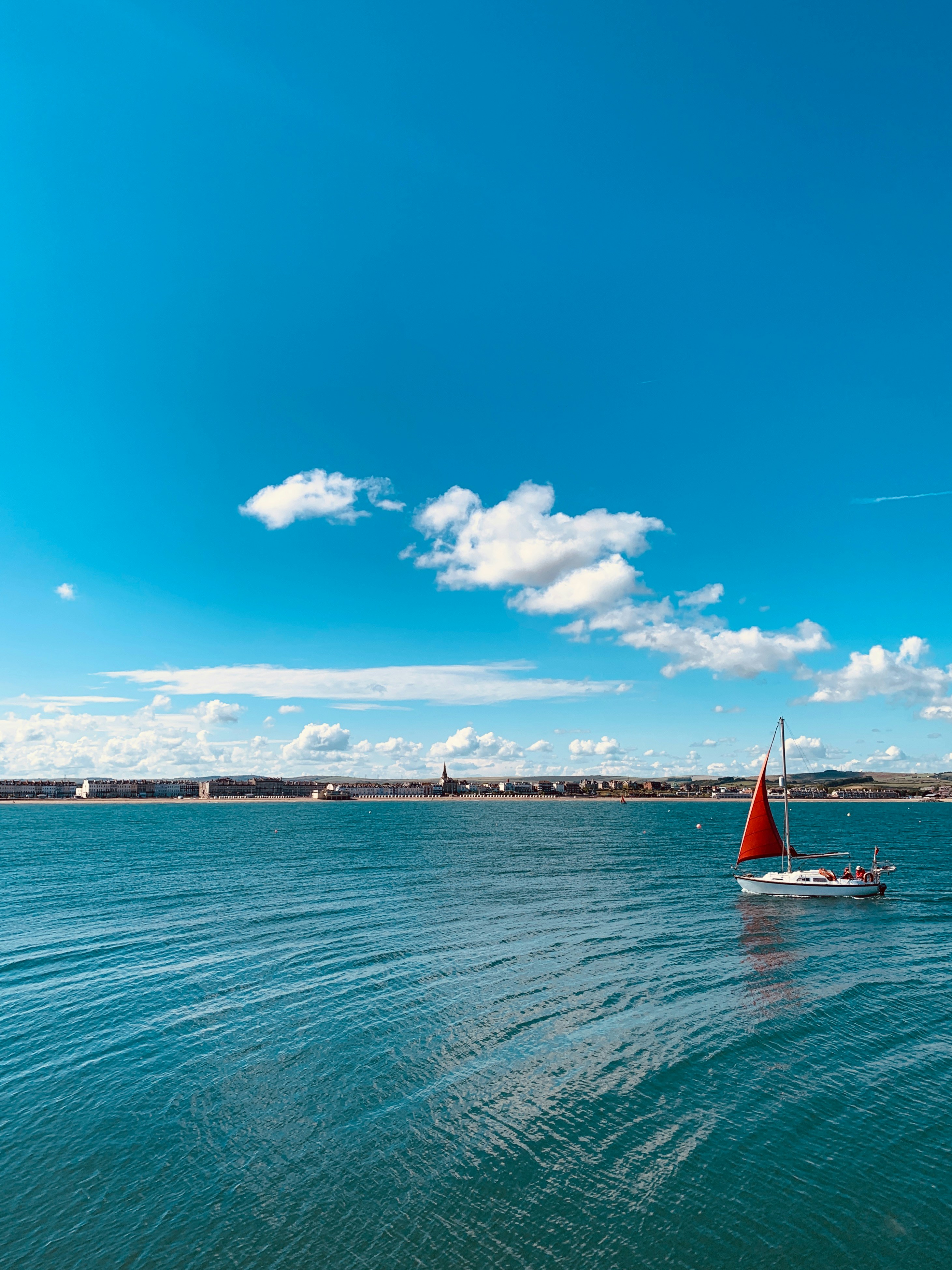 Sailboat Skimming a Calm Coastal Wake