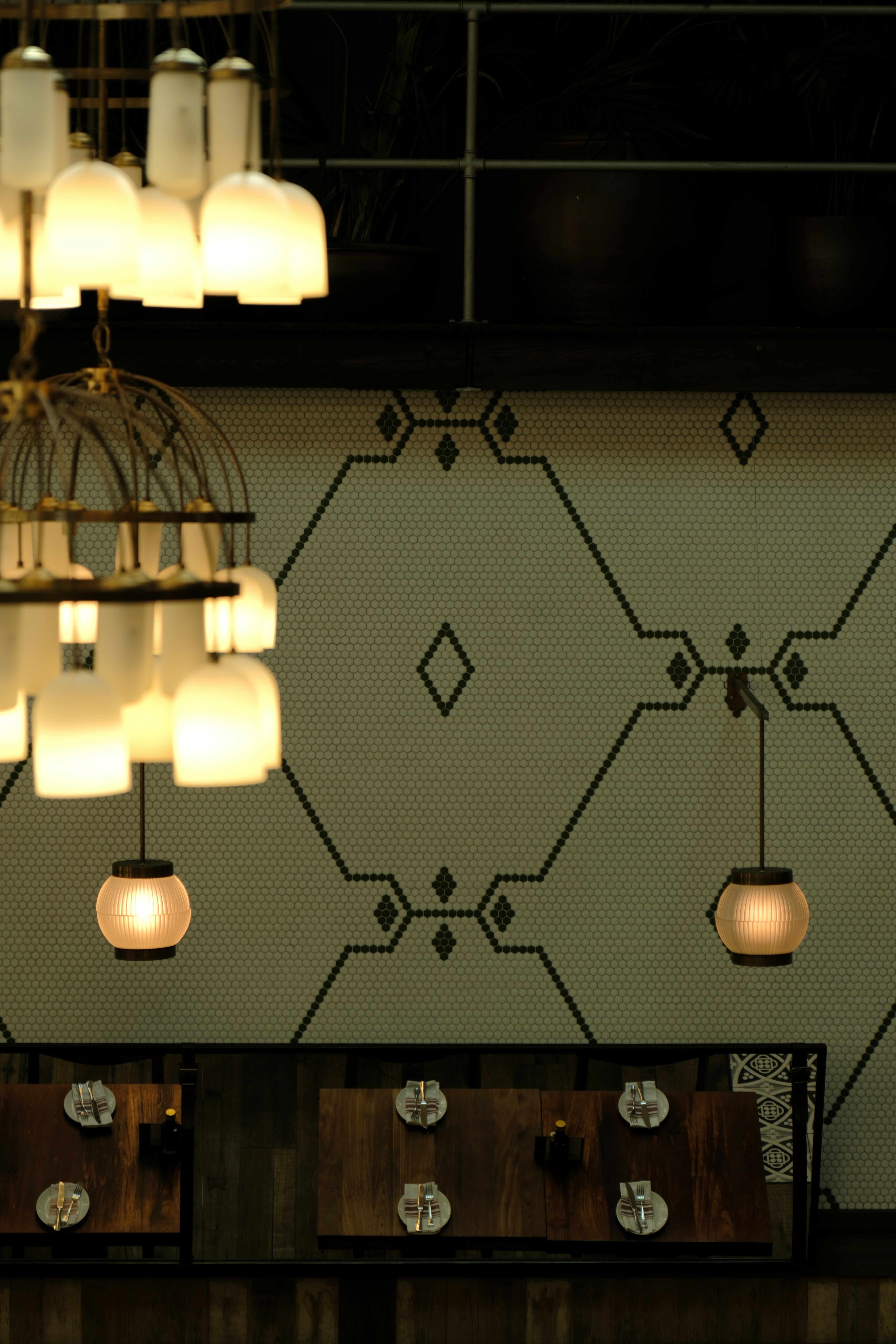 Geometric Glow: Hanging Lamps and Mosaic Wall in Low Light Café