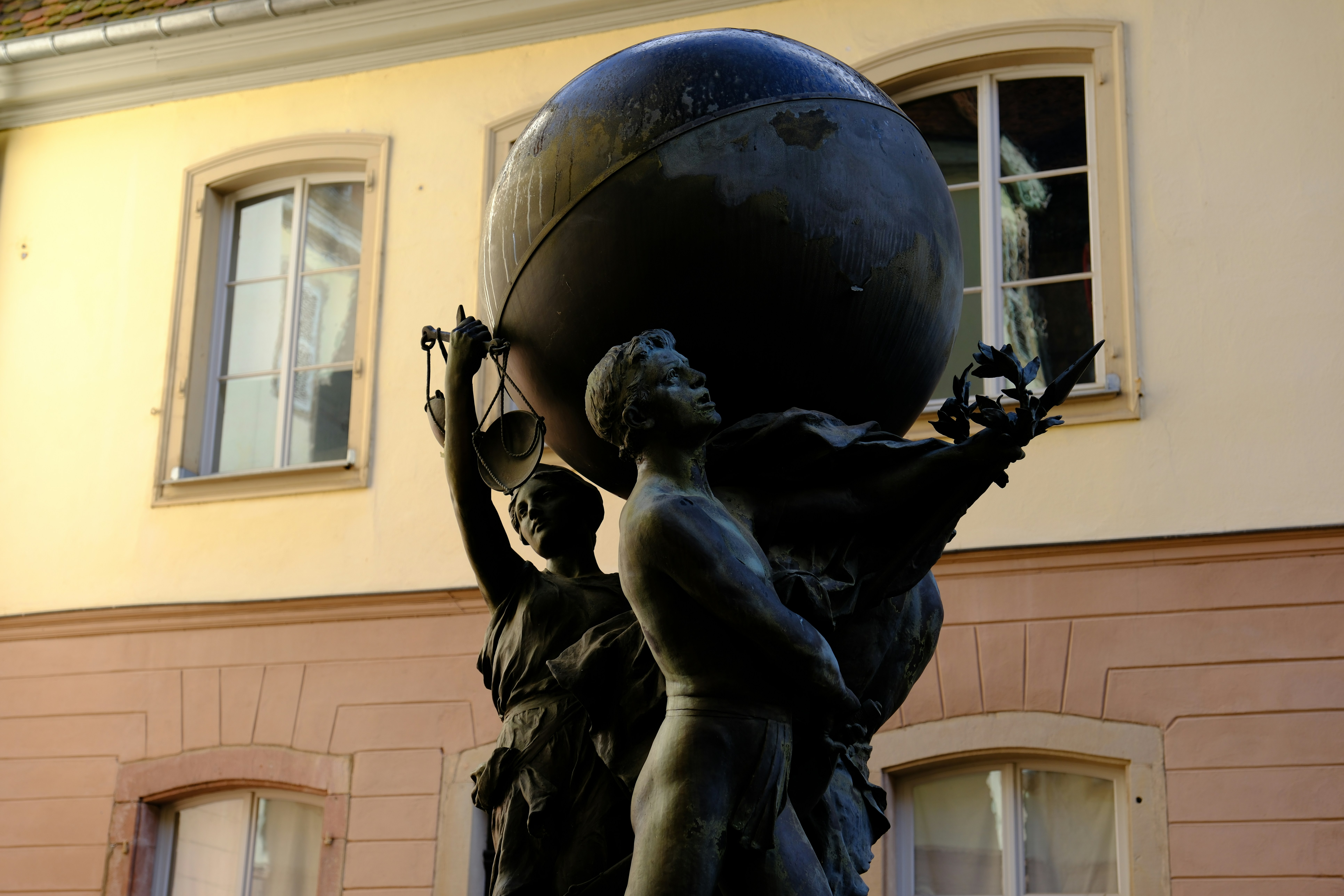 Globe-Bearing Statue: Echoes of Strength under a Golden Window