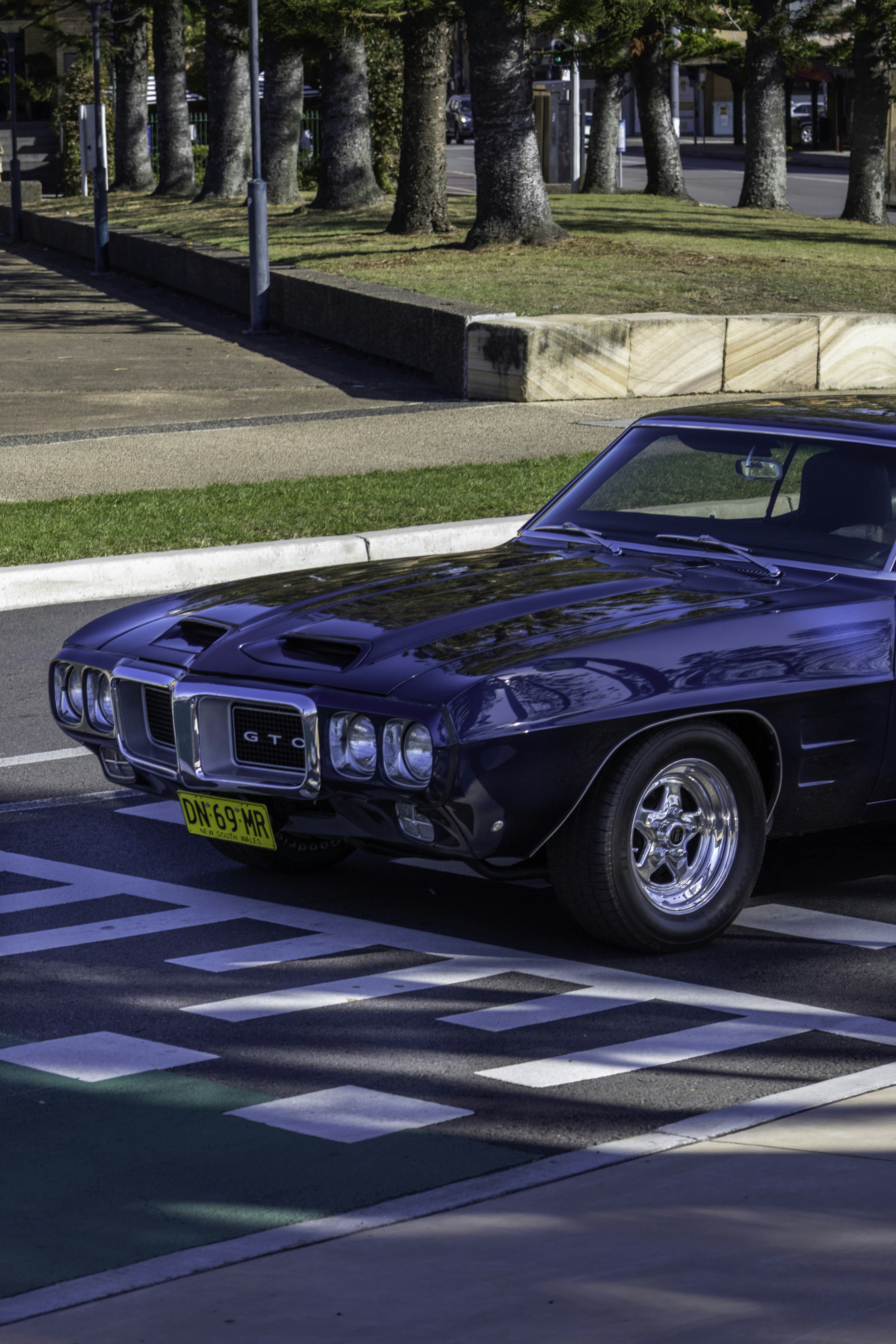 Blue Classic: A Hooded Glimpse of a Muscle Car in Parking Lot Lines