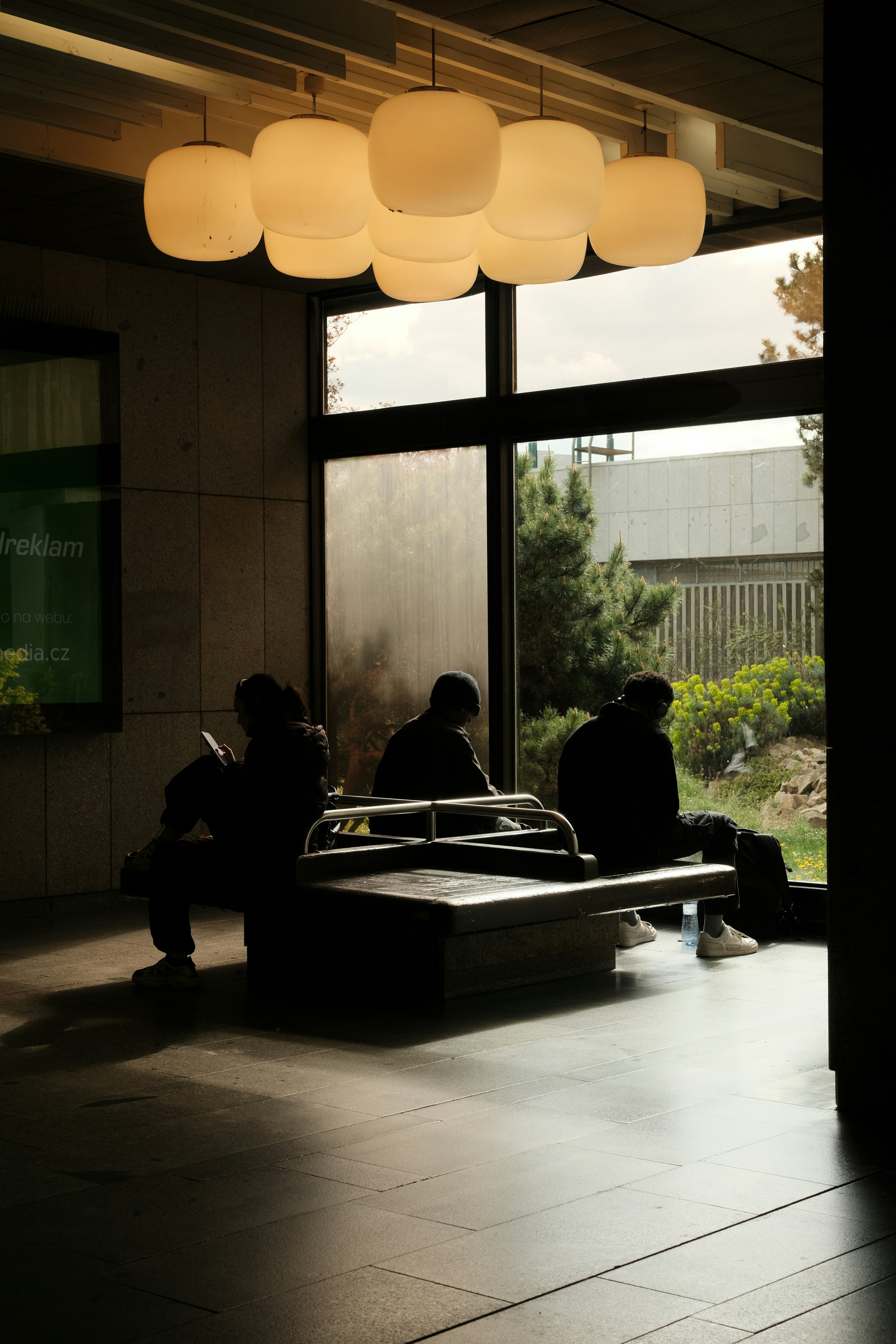 Quiet Pause in the Modern Lobby: silhouettes beneath soft overhead globes