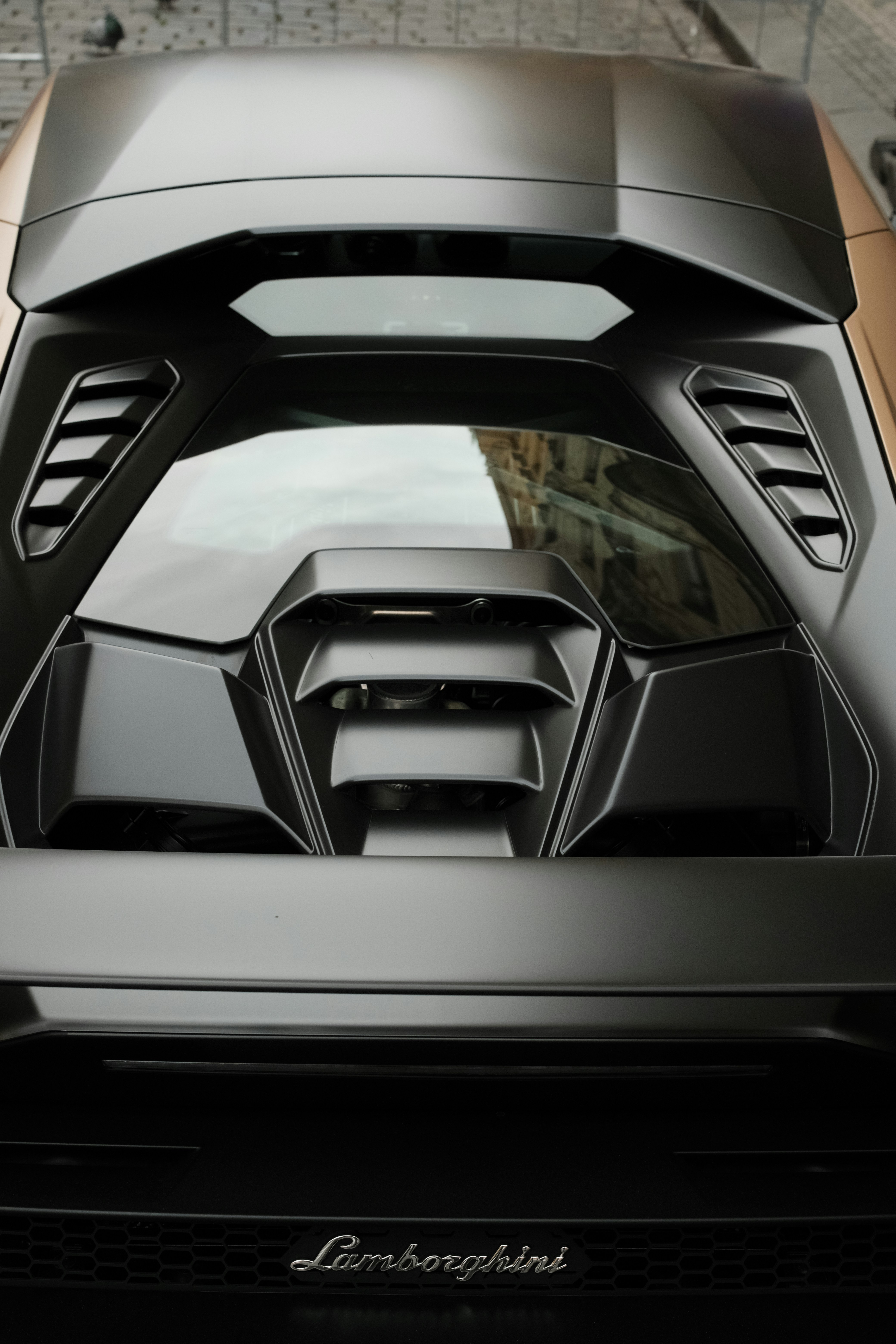 Low-angle view of a matte Lamborghini engine bay with signature badge