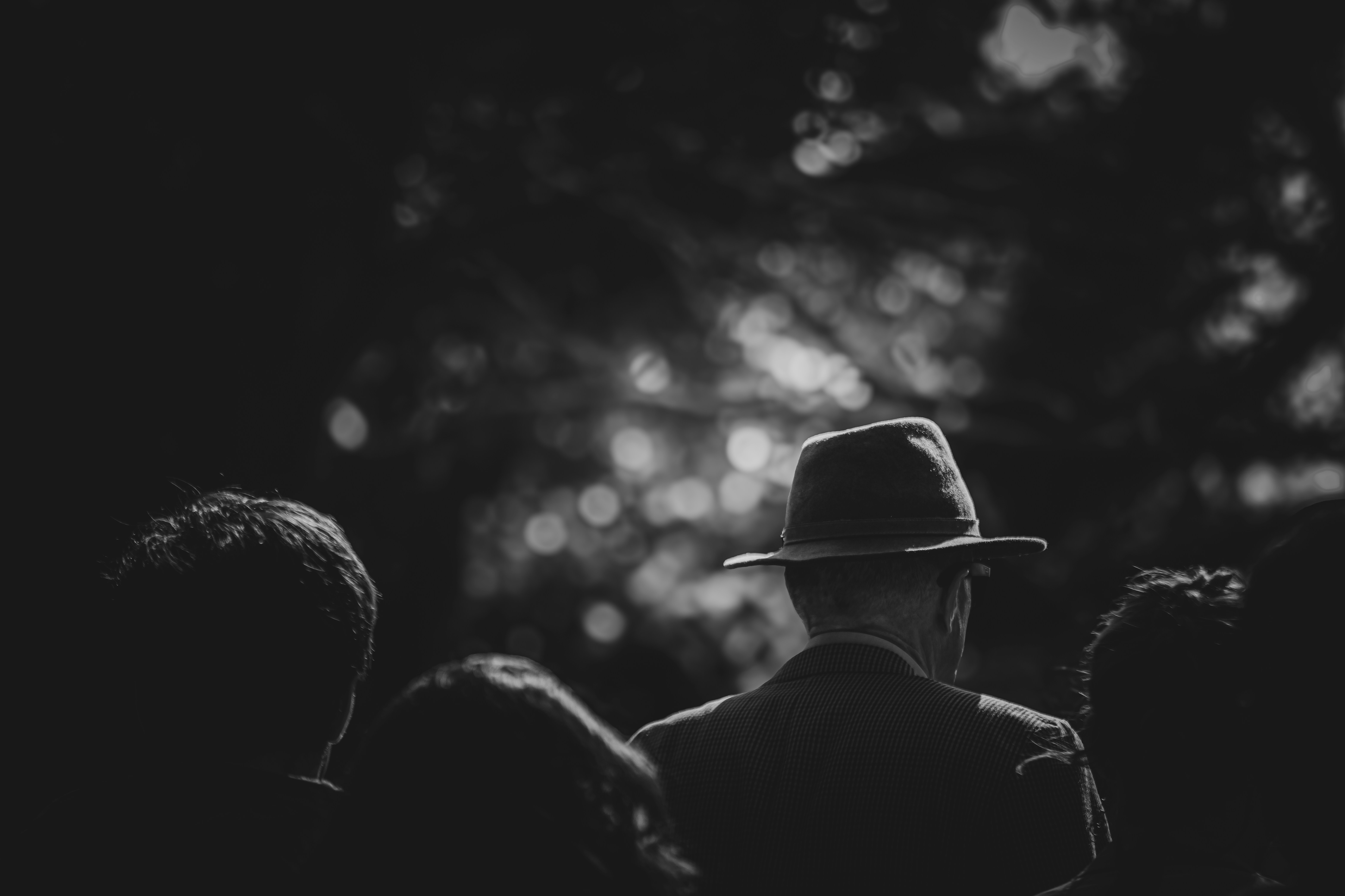 Whispers in the Back Row: A Lone Fedora Amid Silent Heads