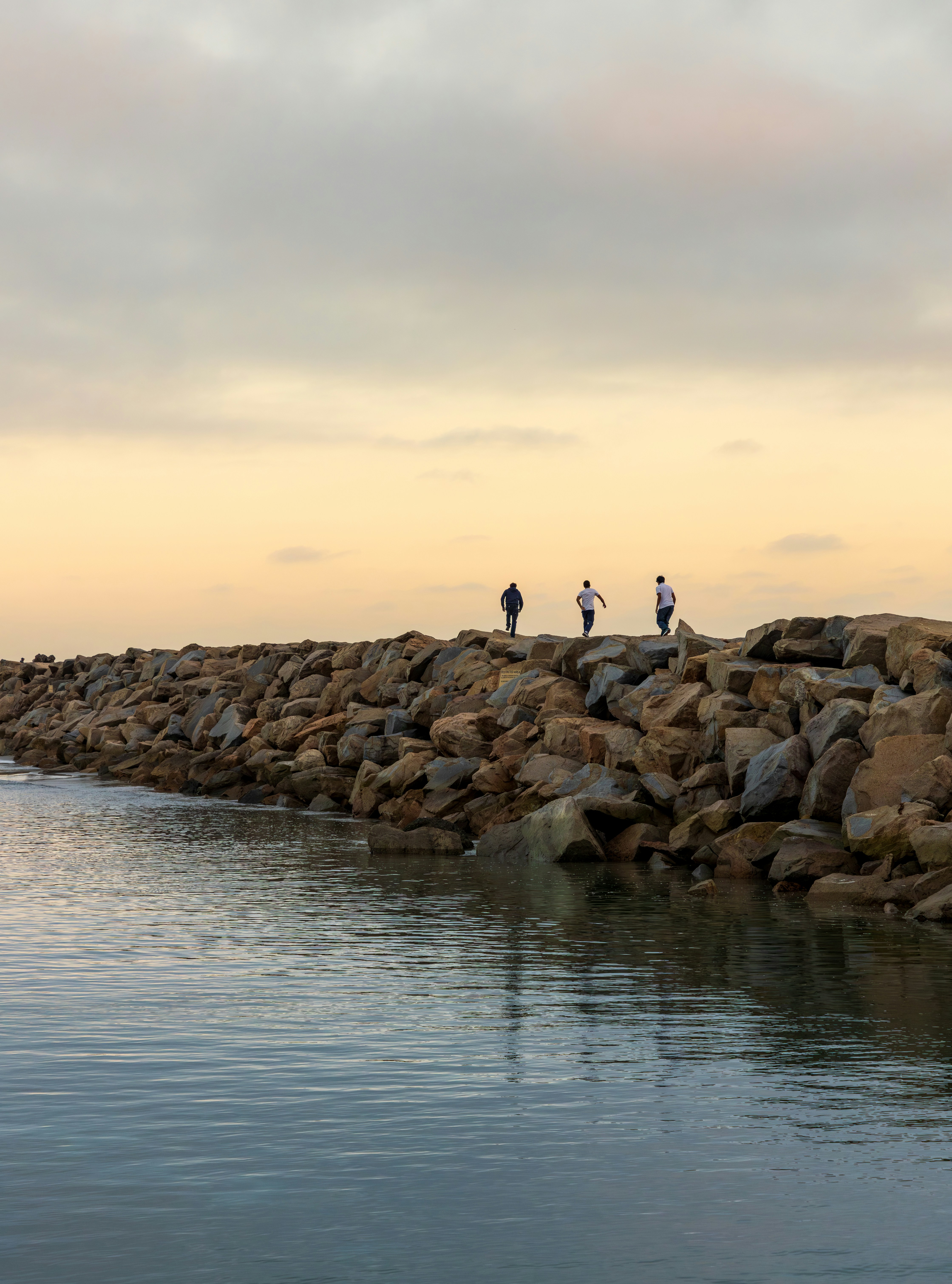 Three Silhouettes on a Breakwater at Dusk