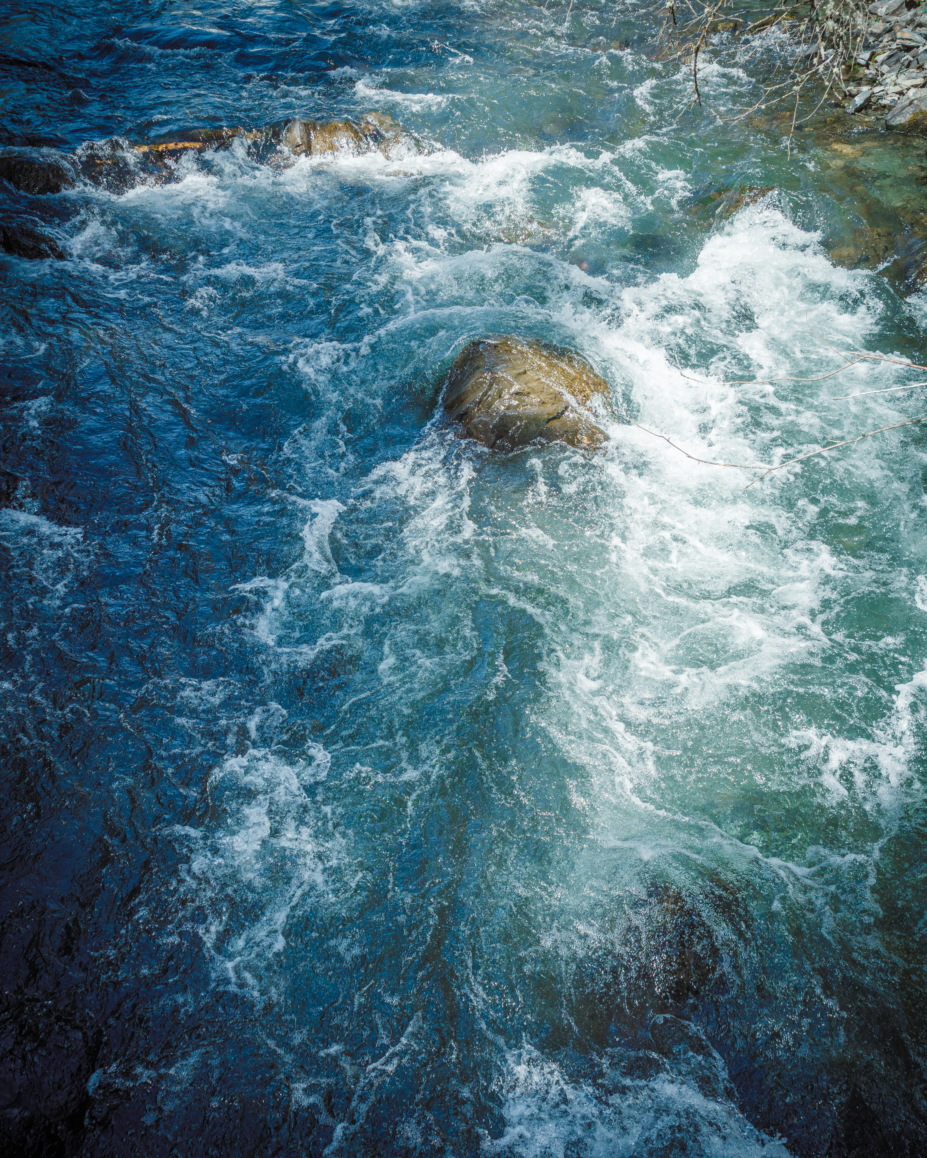 Rushing Aquatic Blues: Light, Foam, and a Central Boulder