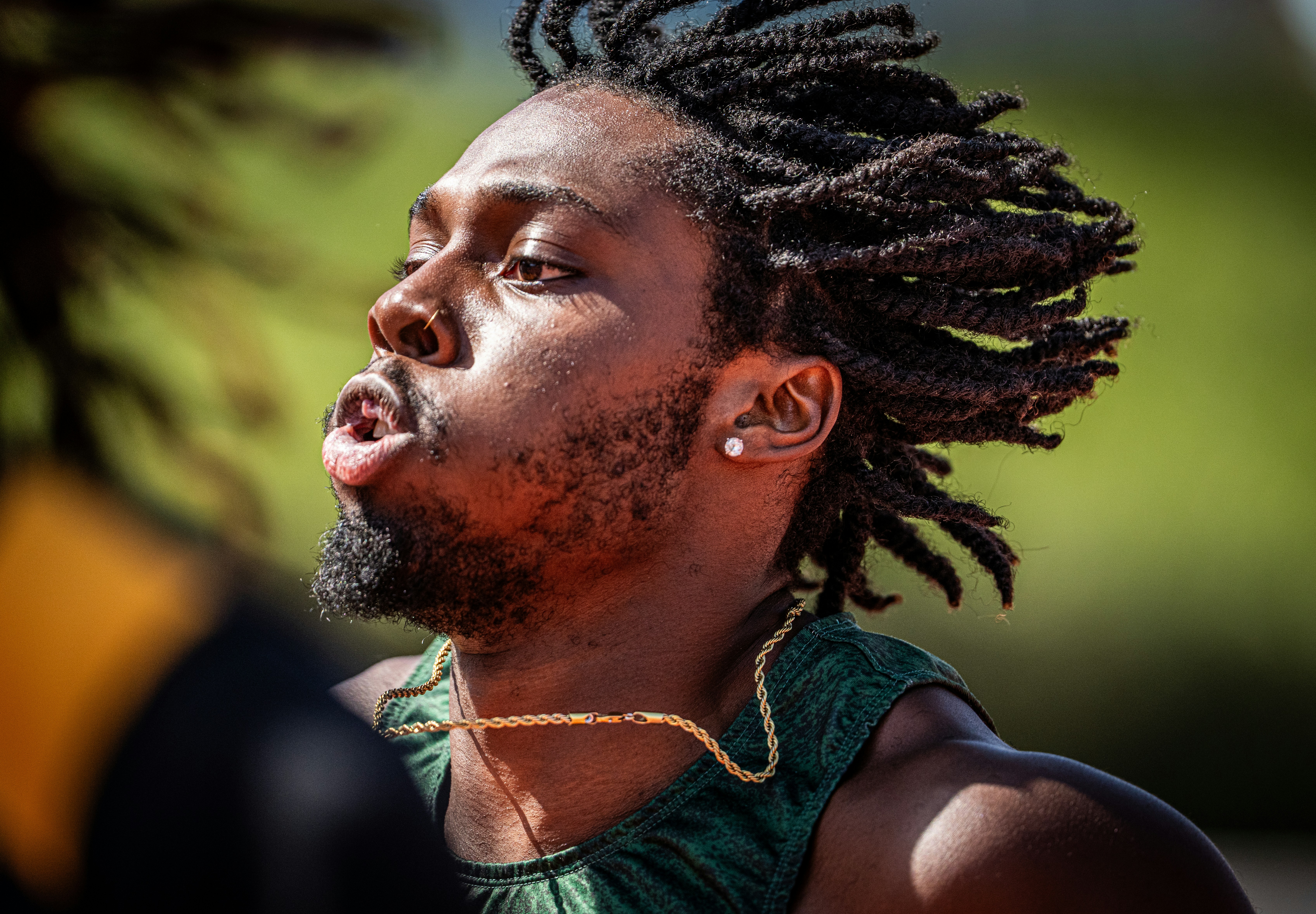 Close-up of a determined runner mid-stride with wind-swept dreadlocks