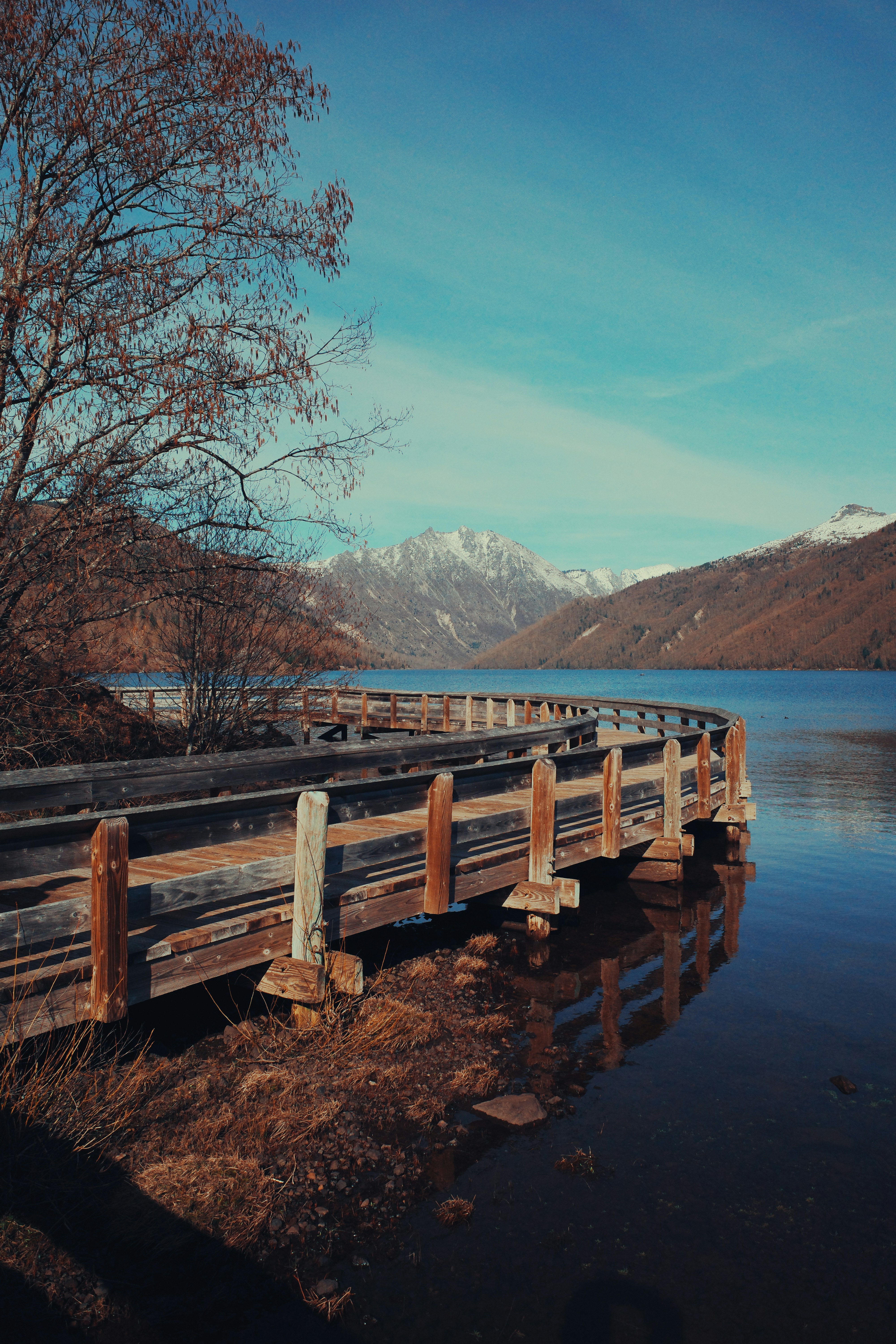 Wooden Pier Reaches Toward Snow-Kissed Mountains Across a Quiet Lake